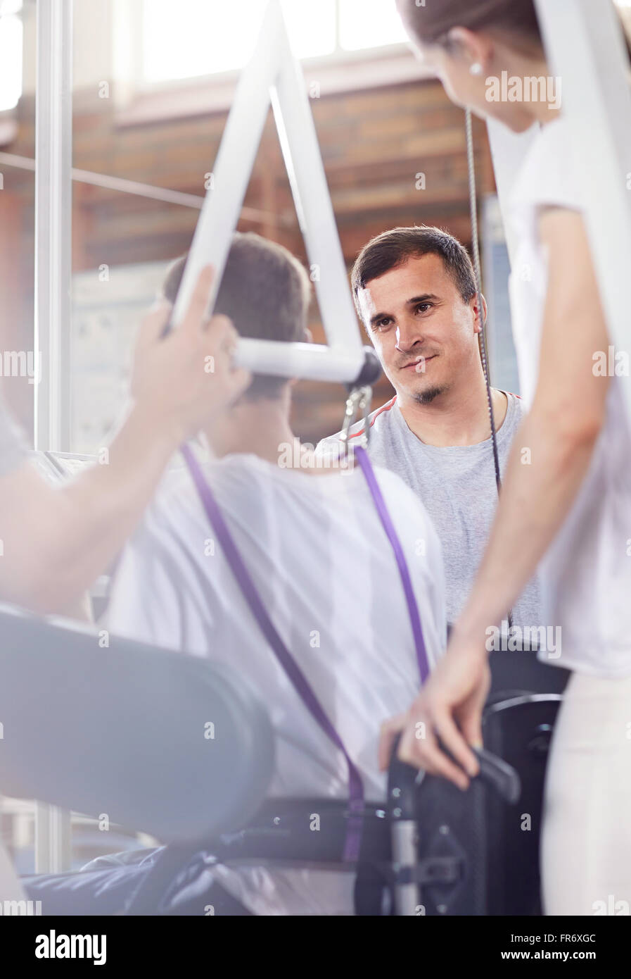 Physical therapists connecting man to equipment Stock Photo - Alamy
