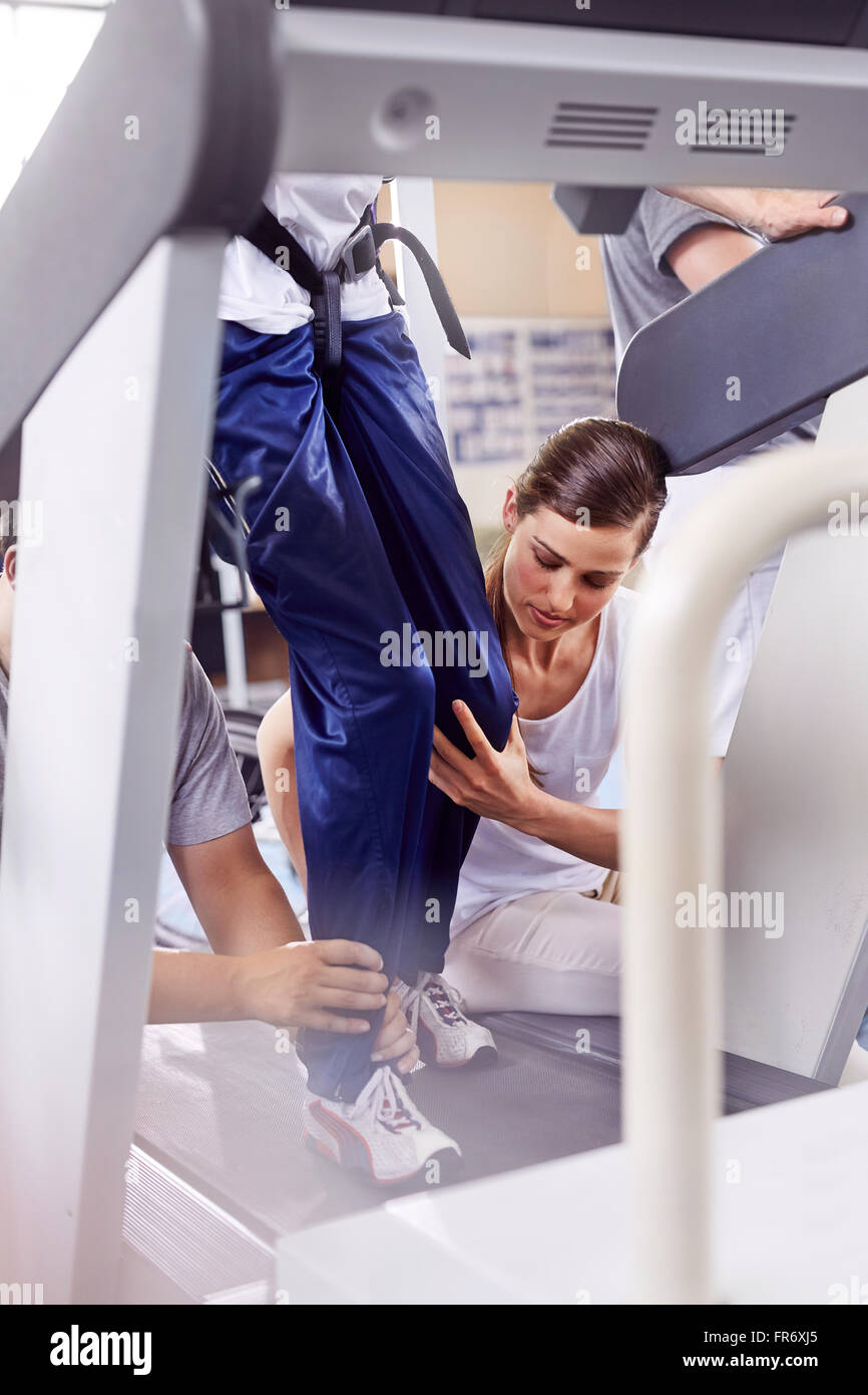 Physical therapists guiding man on treadmill Stock Photo - Alamy