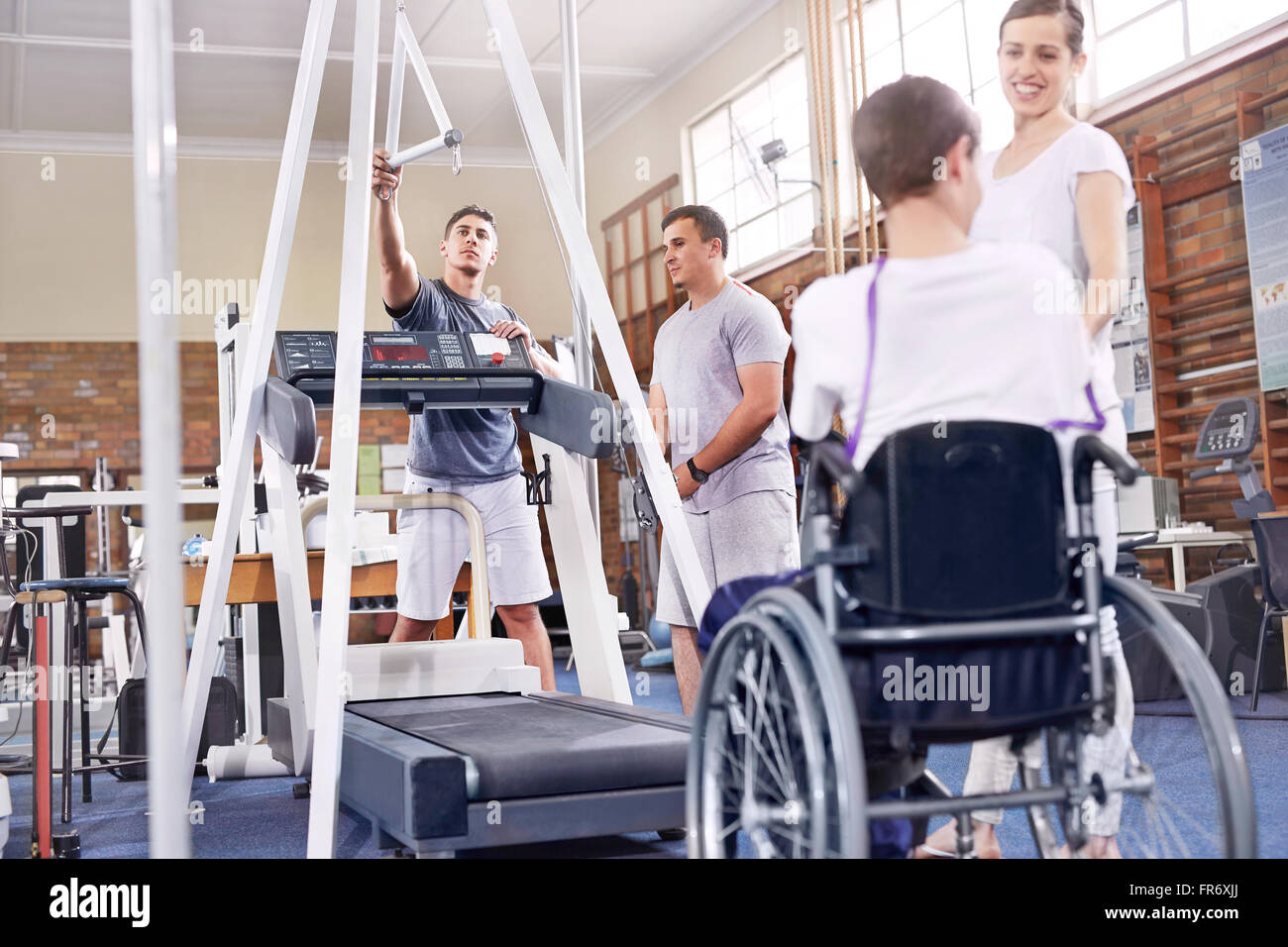 Physical therapists preparing treadmill for man in wheelchair Stock ...