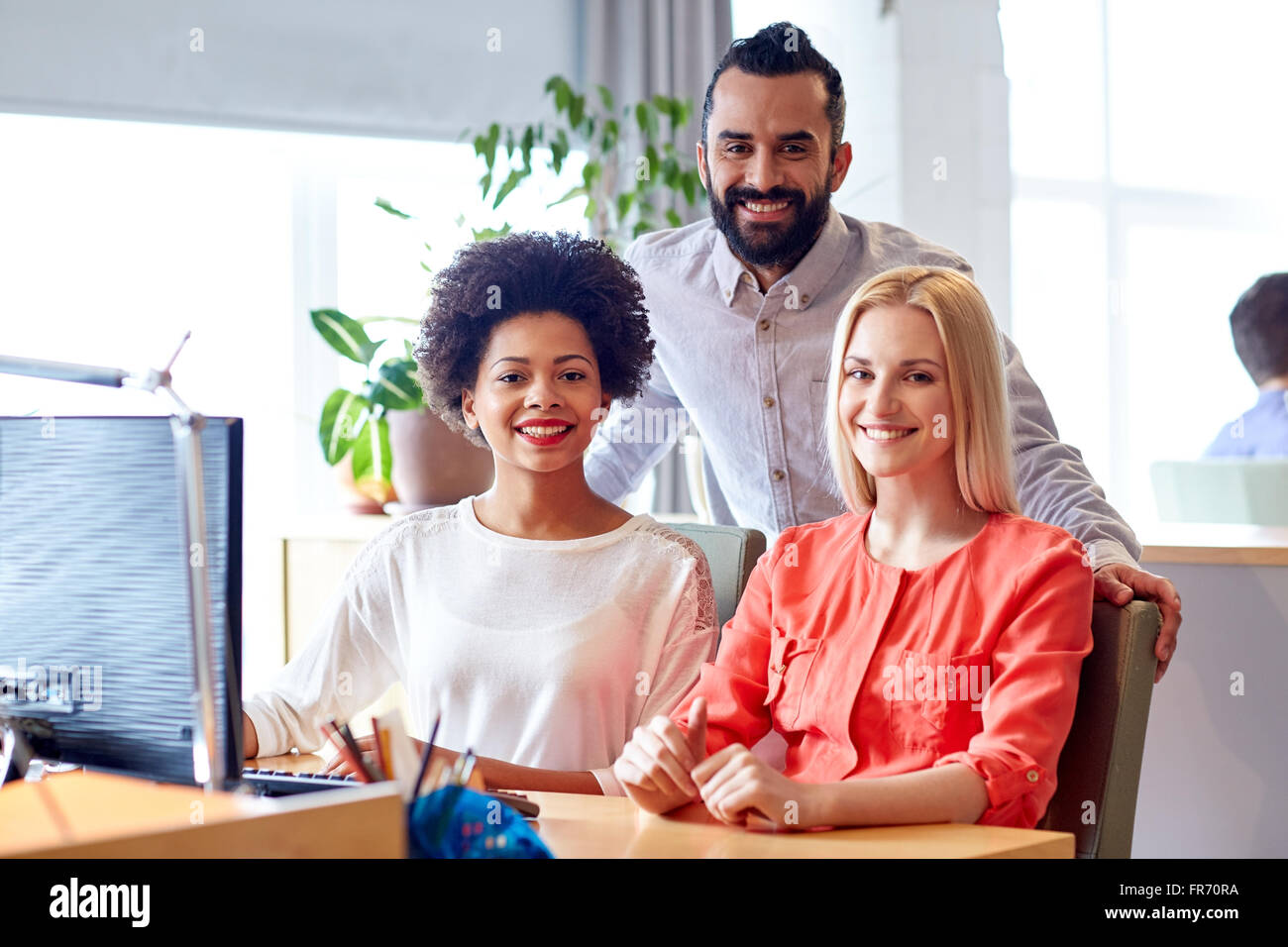 happy creative team with computer in office Stock Photo - Alamy