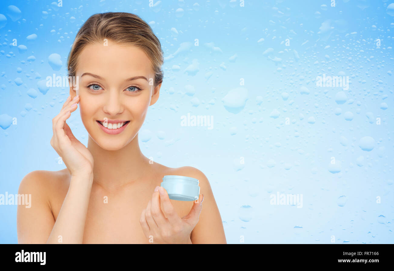 happy young woman applying cream to her face Stock Photo - Alamy