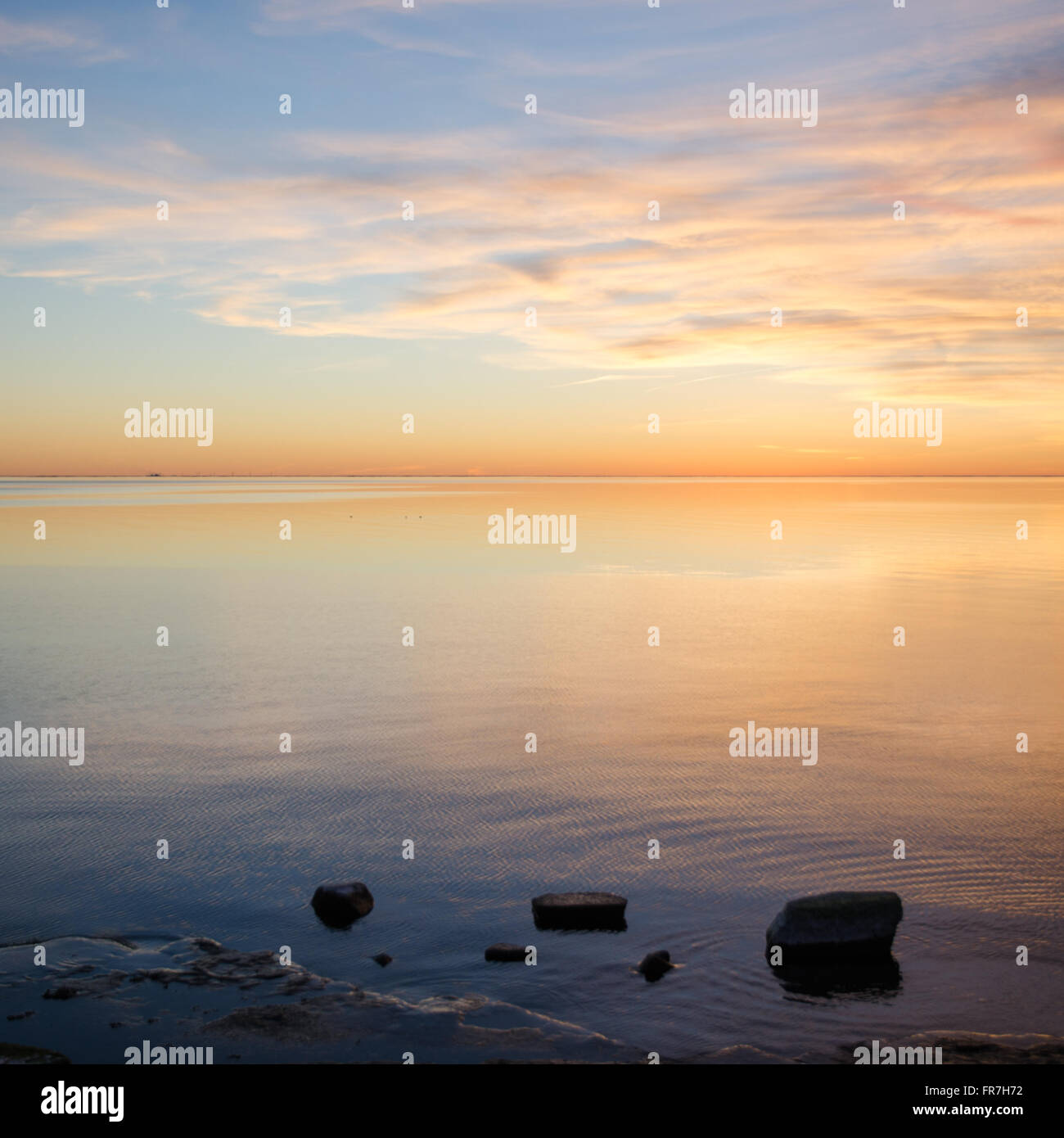 Bright and colorful sunset view by a coast with calm water Stock Photo ...