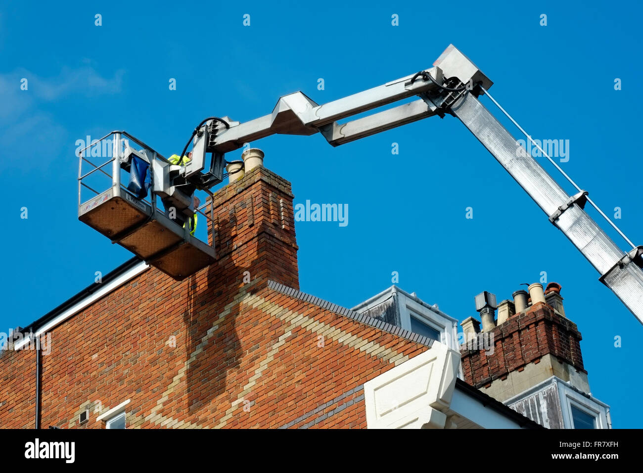 men working in large cherry picker on house roof england uk Stock Photo ...