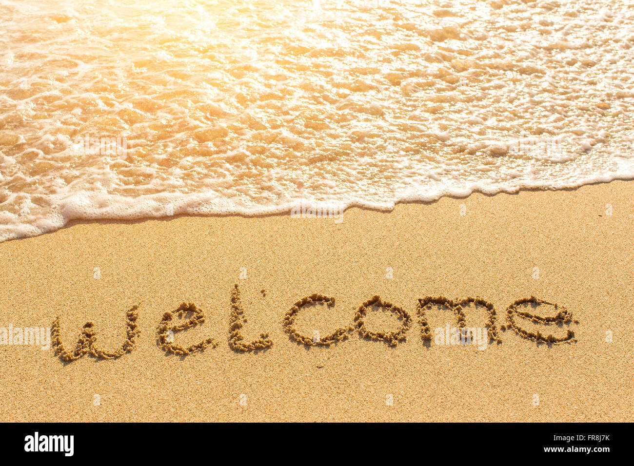 Welcome - drawn on beach sand, soft wave with solar flares Stock Photo ...