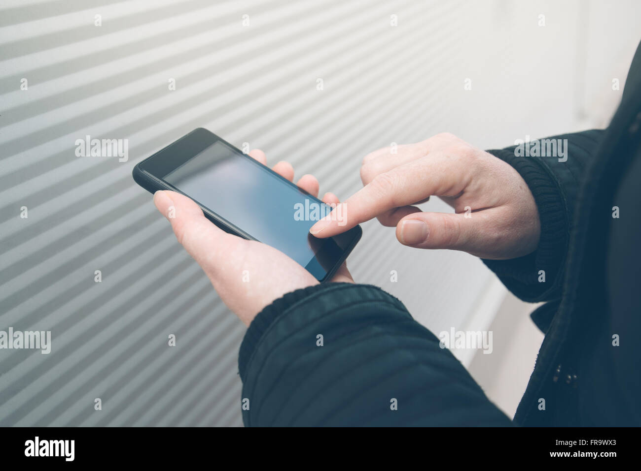 Woman using smartphone on the street, facing the wall while holding ...