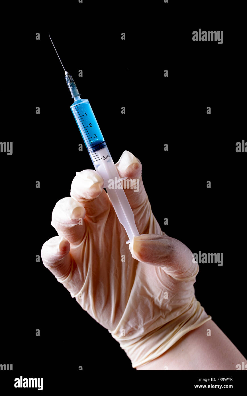 hand with surgical glove and syringe for injection on black background ...