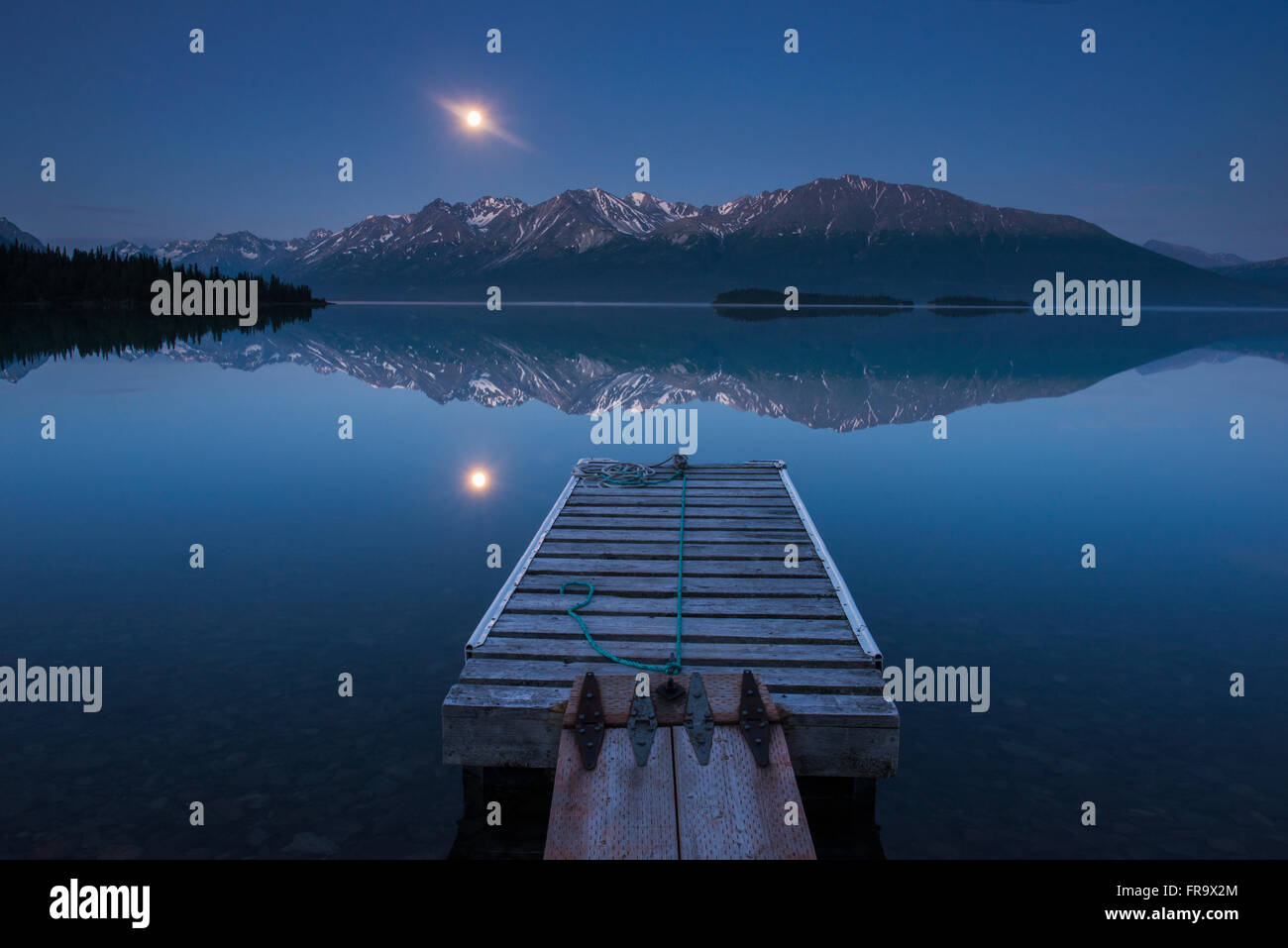 Boat dock with a full moon rising over the Chigmit Mountains at Lake ...