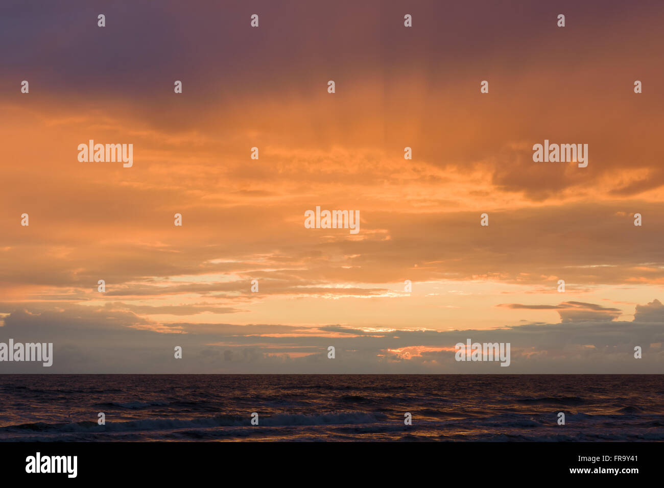 the sun sits down over the sea drawing silhouettes ashore Stock Photo ...