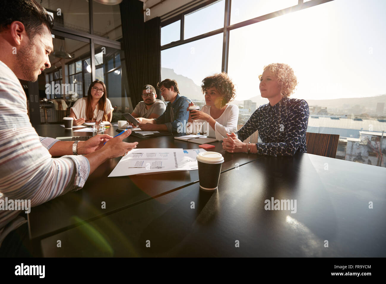 Portrait of creative team sitting around a table discussing new project ...