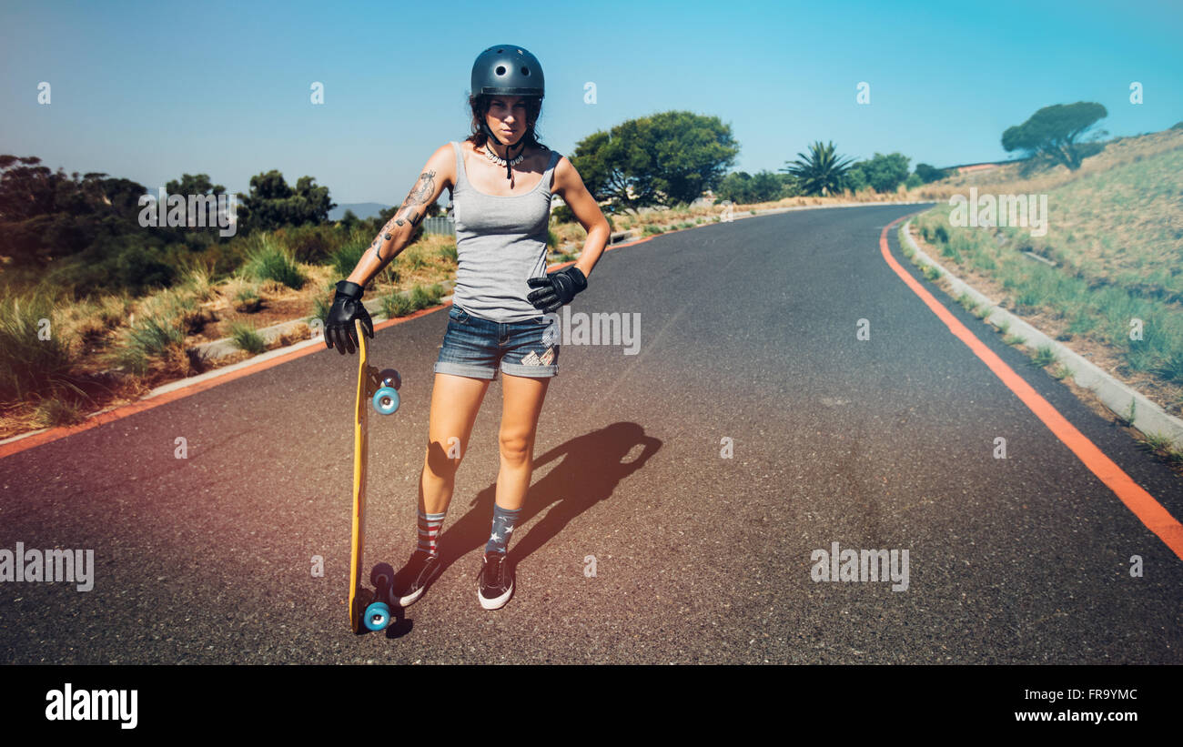Full length portrait of young woman standing on a countryside highway ...