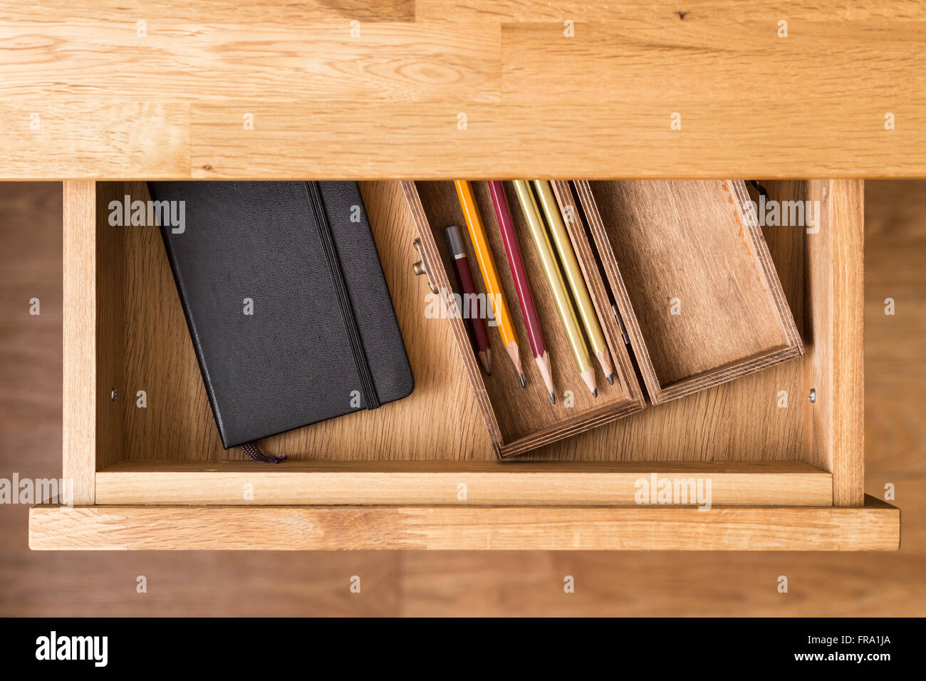 Notebook and pencils in open desk drawer top view image. Drawing ...