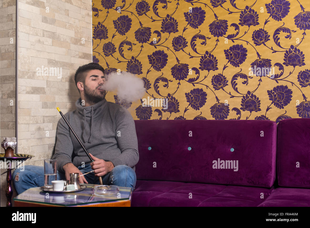 Young Man Smoking Shisha At Arabic Restaurant - Man Exhaling Smoke ...