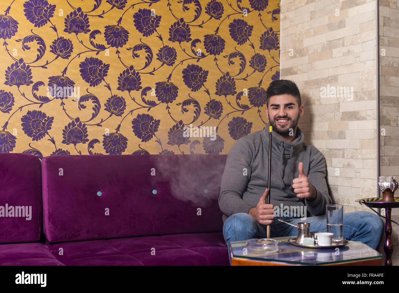 Young Man Smoking Shisha At Arabic Restaurant - Man Exhaling Smoke ...