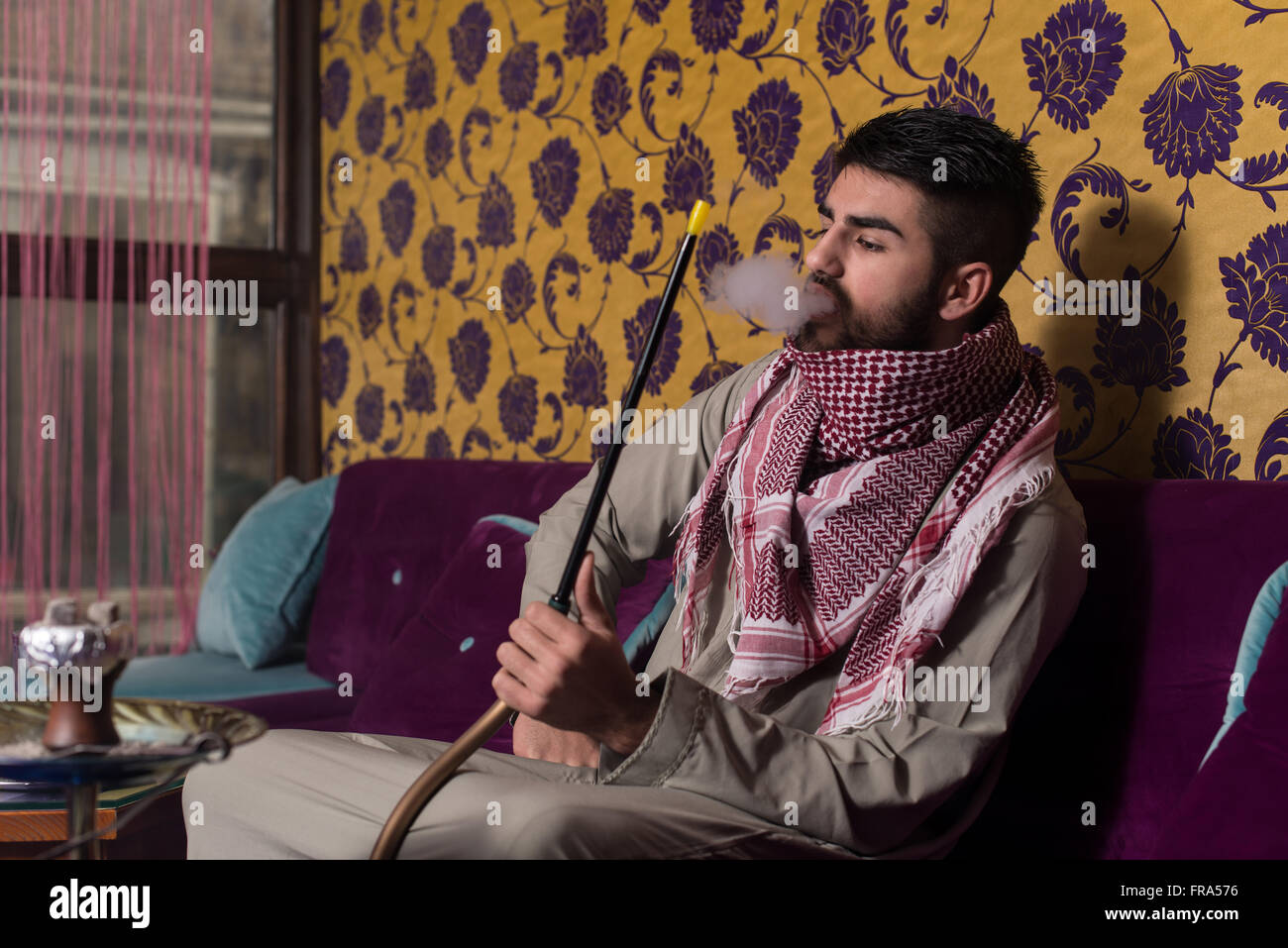 Muslim Man Smoking Shisha At Arabic Restaurant Exhaling Smoke Stock