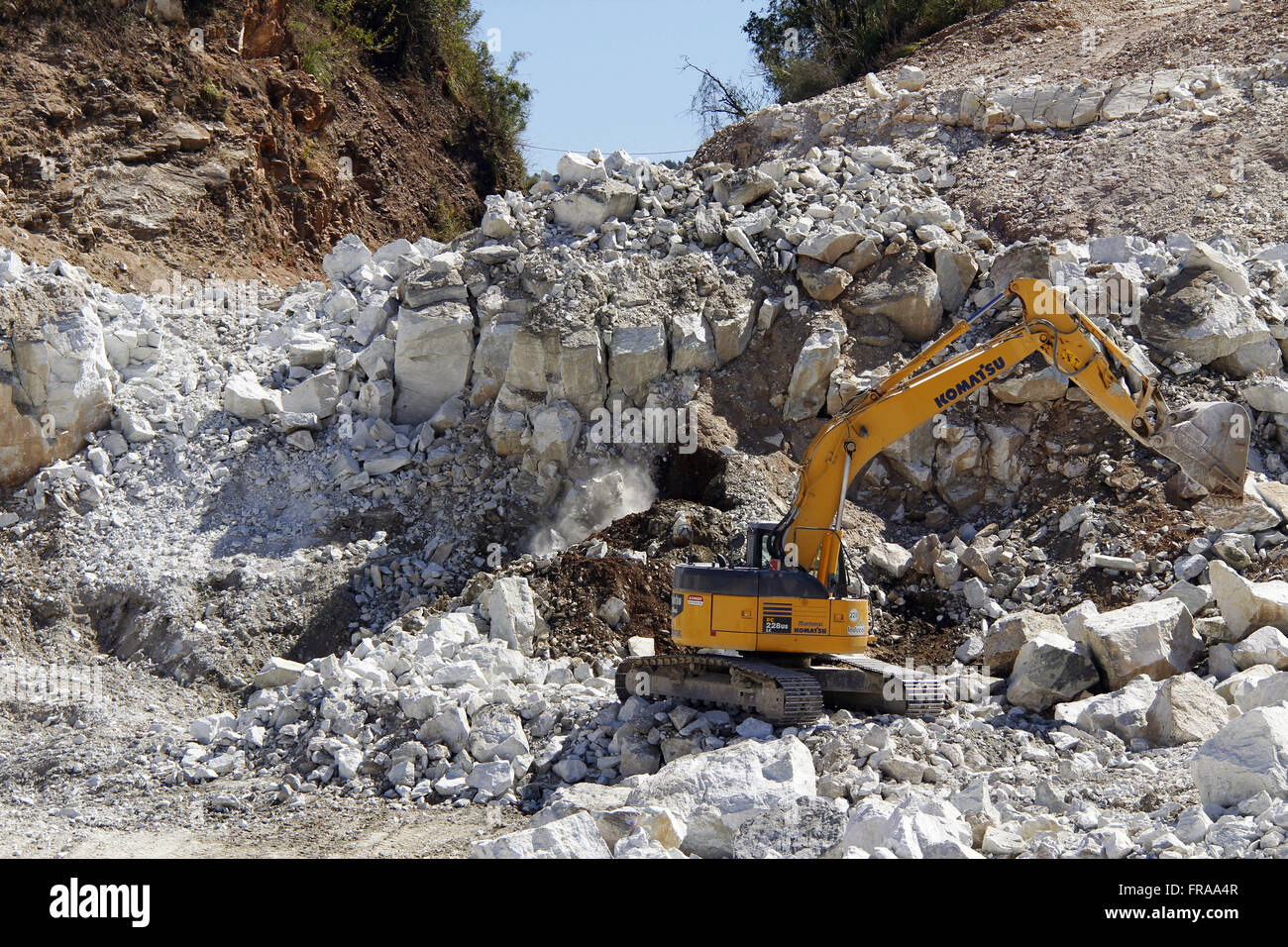 Backhoe moving calcareous rocks broken by explosives in opencast mine ...