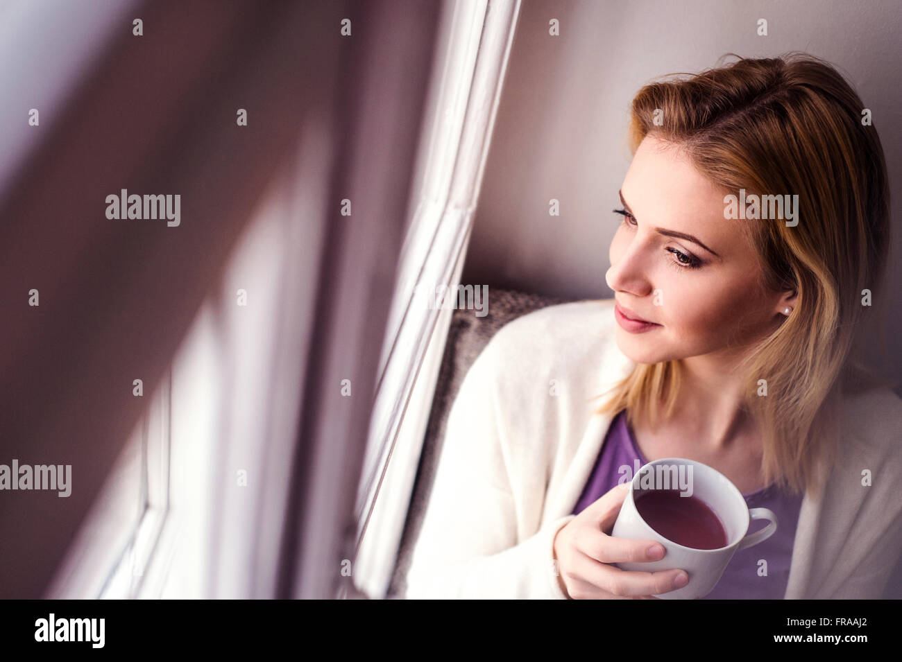 Woman on window sill holding a cup of tea Stock Photo - Alamy