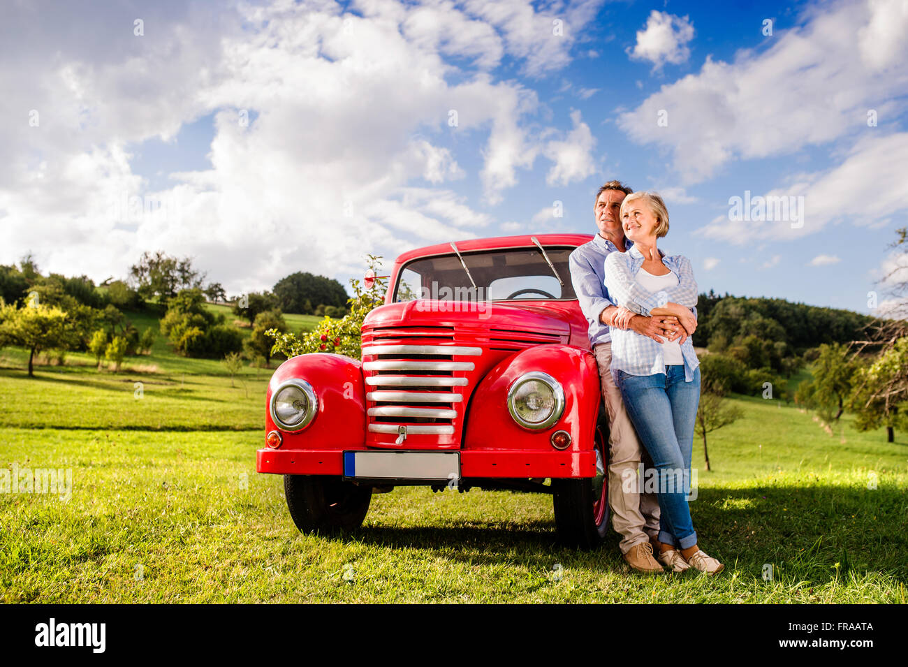 Senior couple hugging, vintage styled red car, sunny nature Stock Photo ...