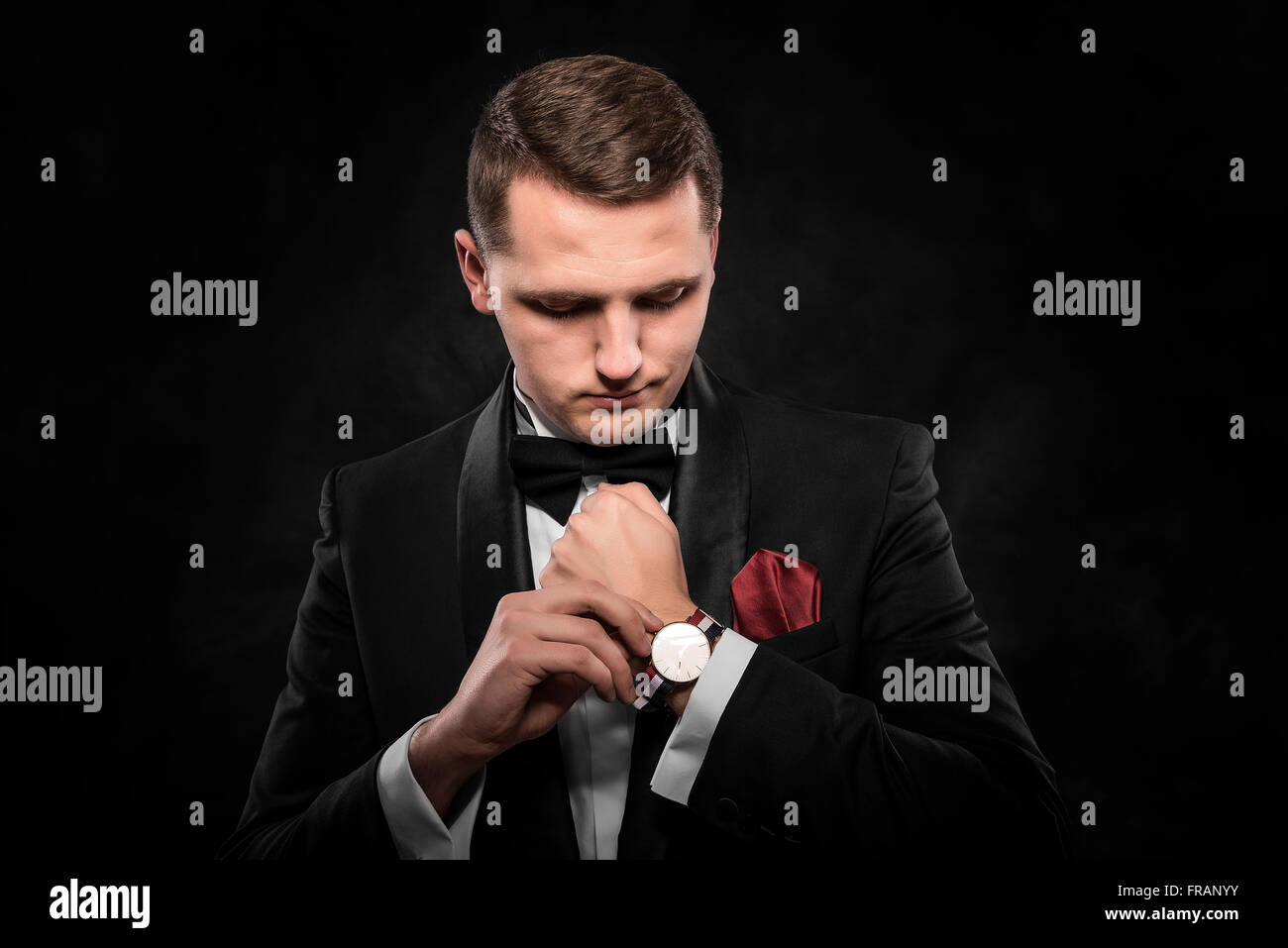Elegant young fashion man looking at his watch Stock Photo - Alamy
