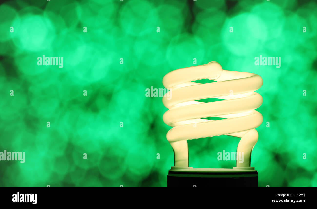 Illuminated compact fluorescent lamp - CFL - on a background of de ...