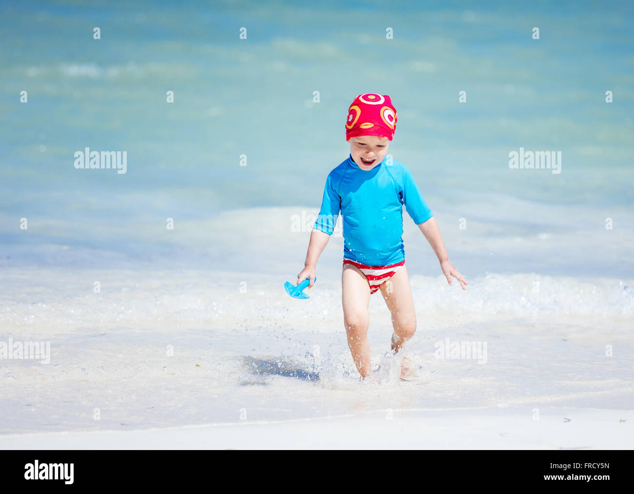 Happy little boy running in breaking waves on the beach Stock Photo - Alamy