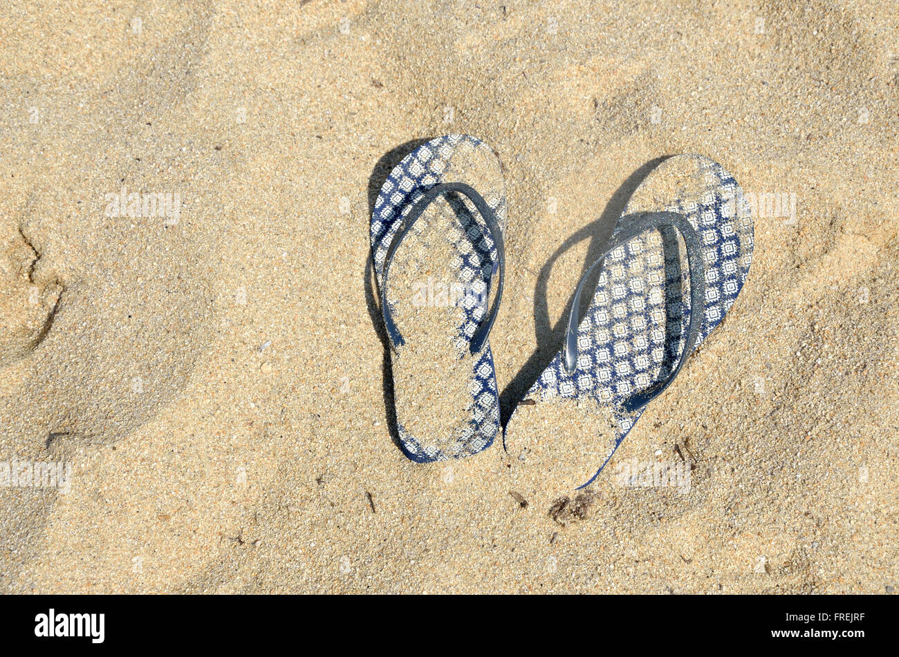 Blue flip flops covered with sand left on beach Stock Photo - Alamy