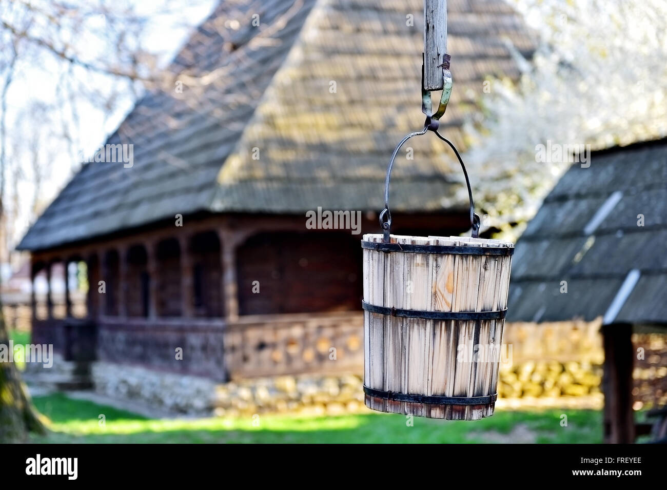 Wooden fountain bucket detail with rural spring scenery in background ...