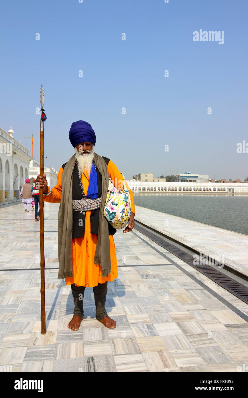 A traditionally dressed Sikh temple guard by the holy pool or sarovar ...