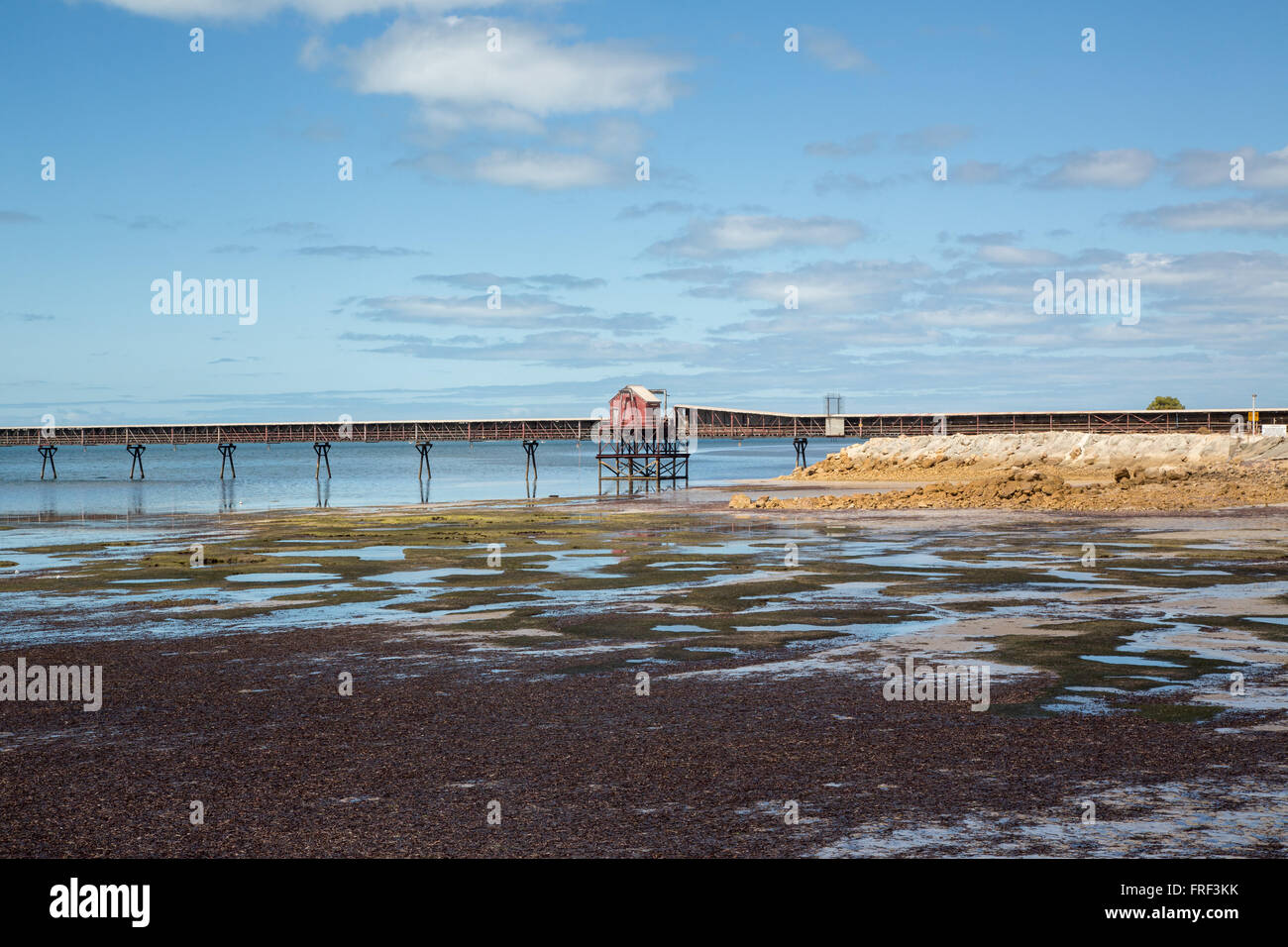 industrial loading jetty with red house, shallow water speckled with ...