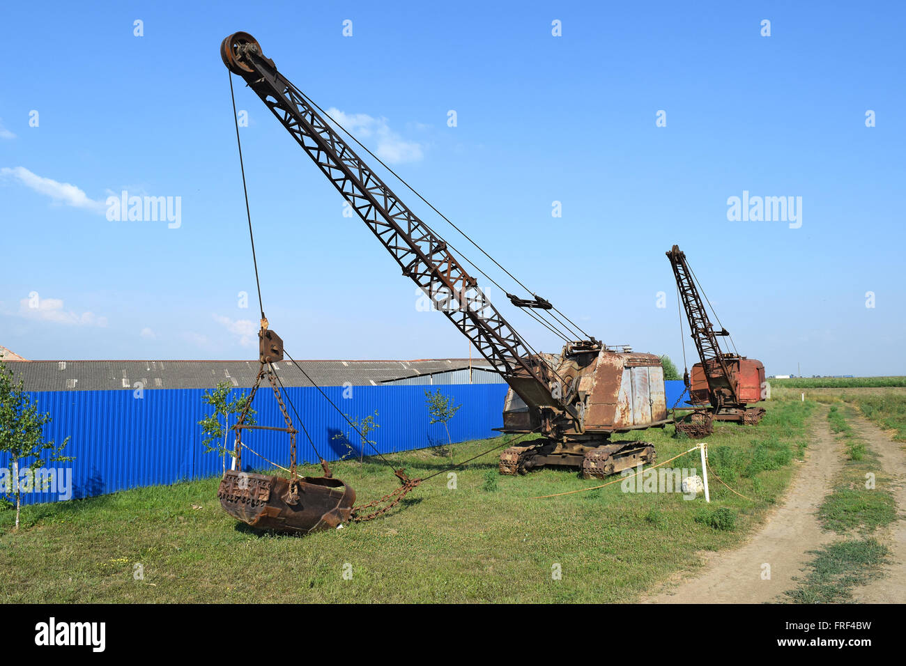 Old dragline near the blue fence. Old equipment for digging the soil in ...