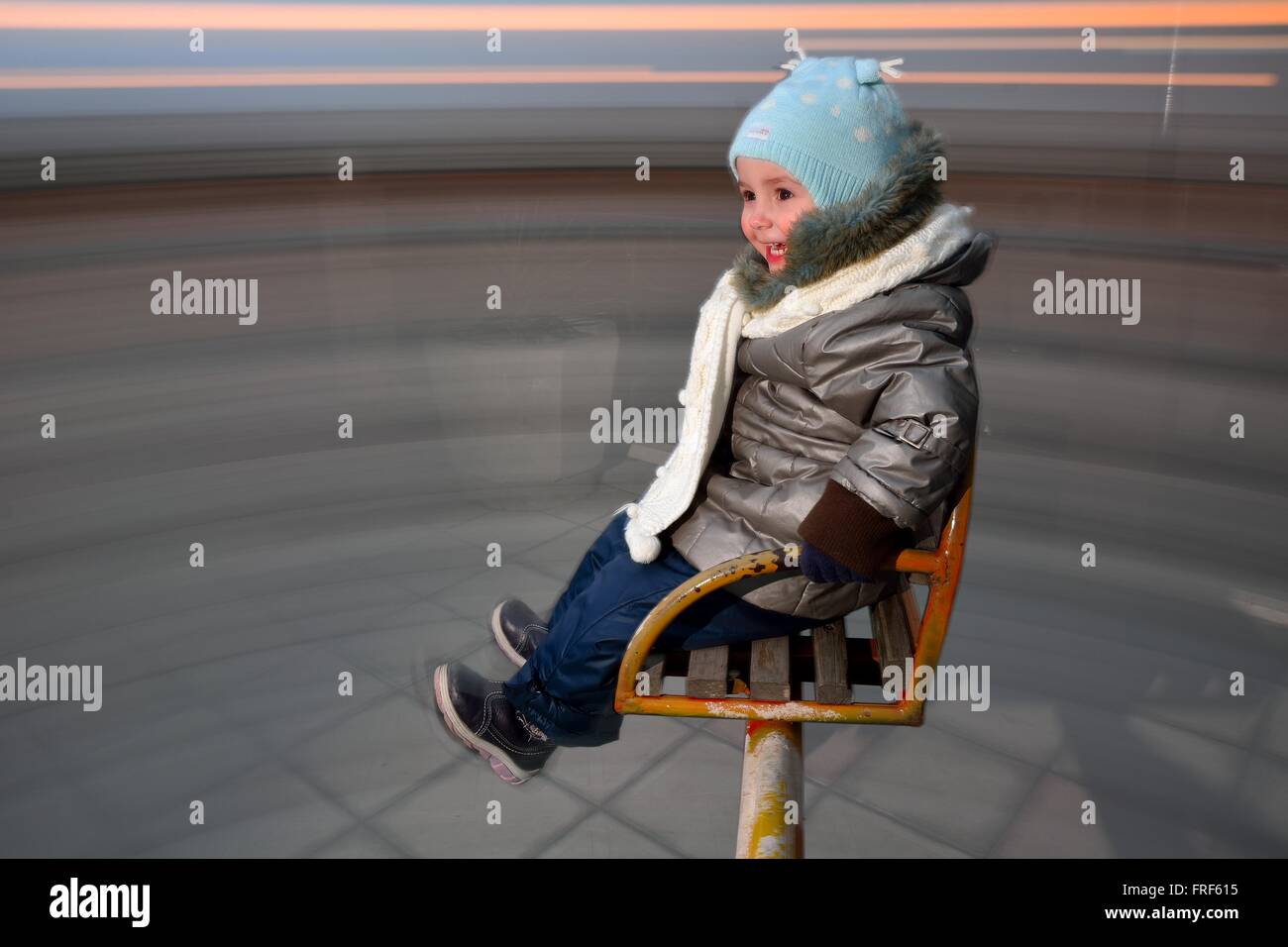 Child spinning on a roundabout. A young girl turning and smiling with ...