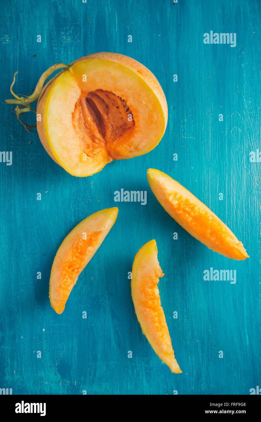 Melon slices on rustic blue background Stock Photo - Alamy