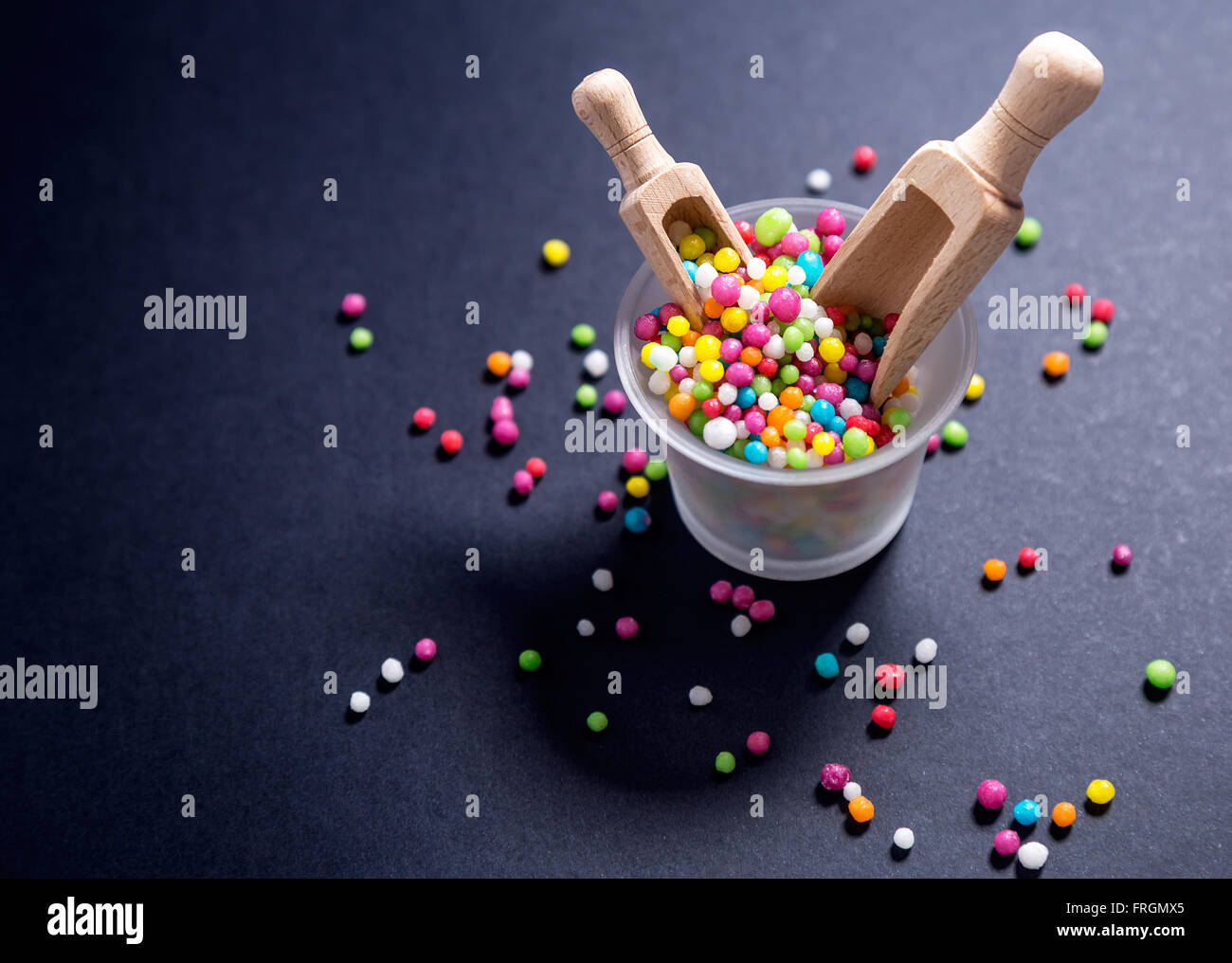 Colored candy,sugar pearls with wood scoop on black background Stock ...
