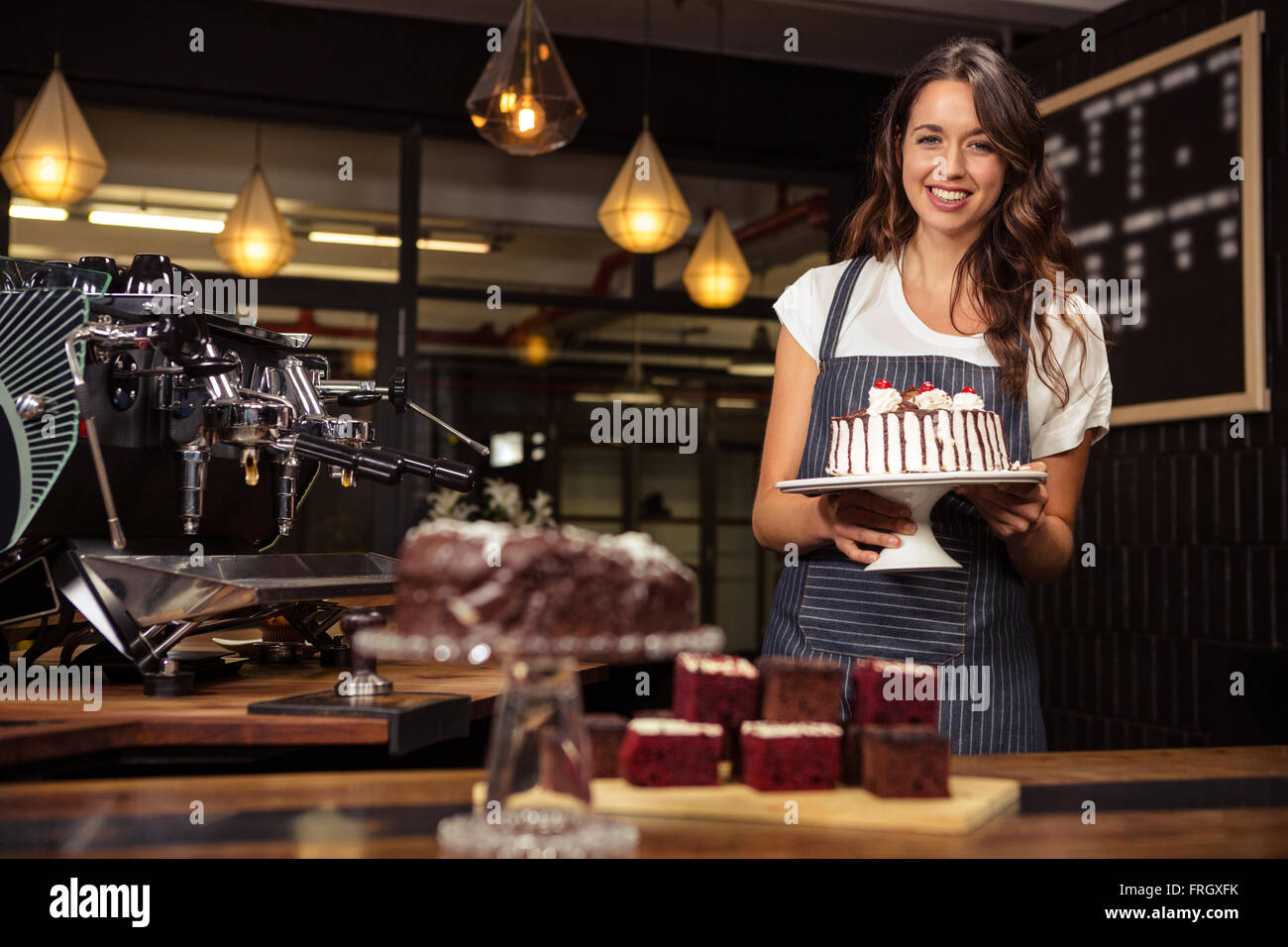 Smiling barista holding plate with cake Stock Photo - Alamy