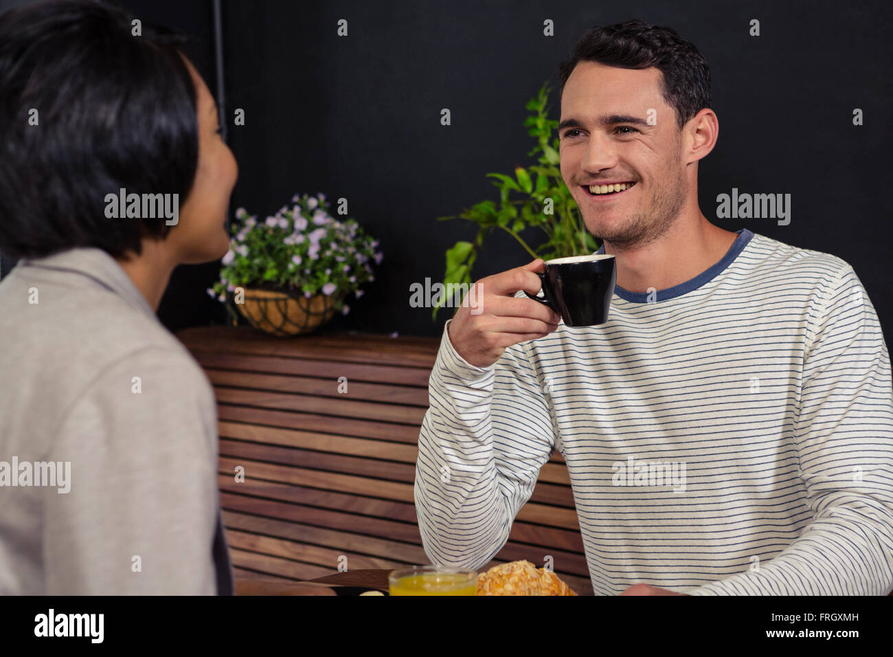 Cute couple talking while eating Stock Photo - Alamy