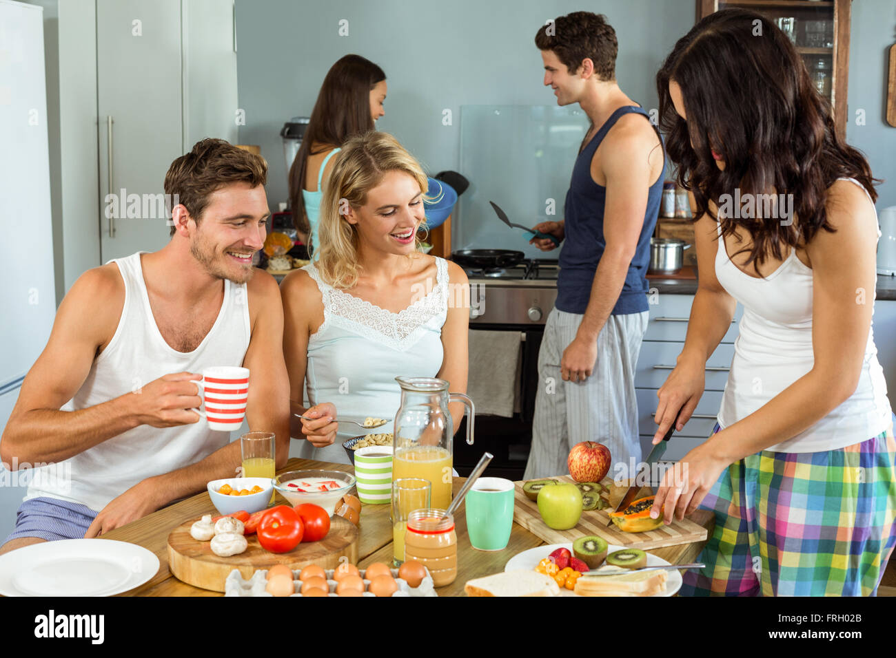 Happy young friends cooking food in kitchen Stock Photo - Alamy