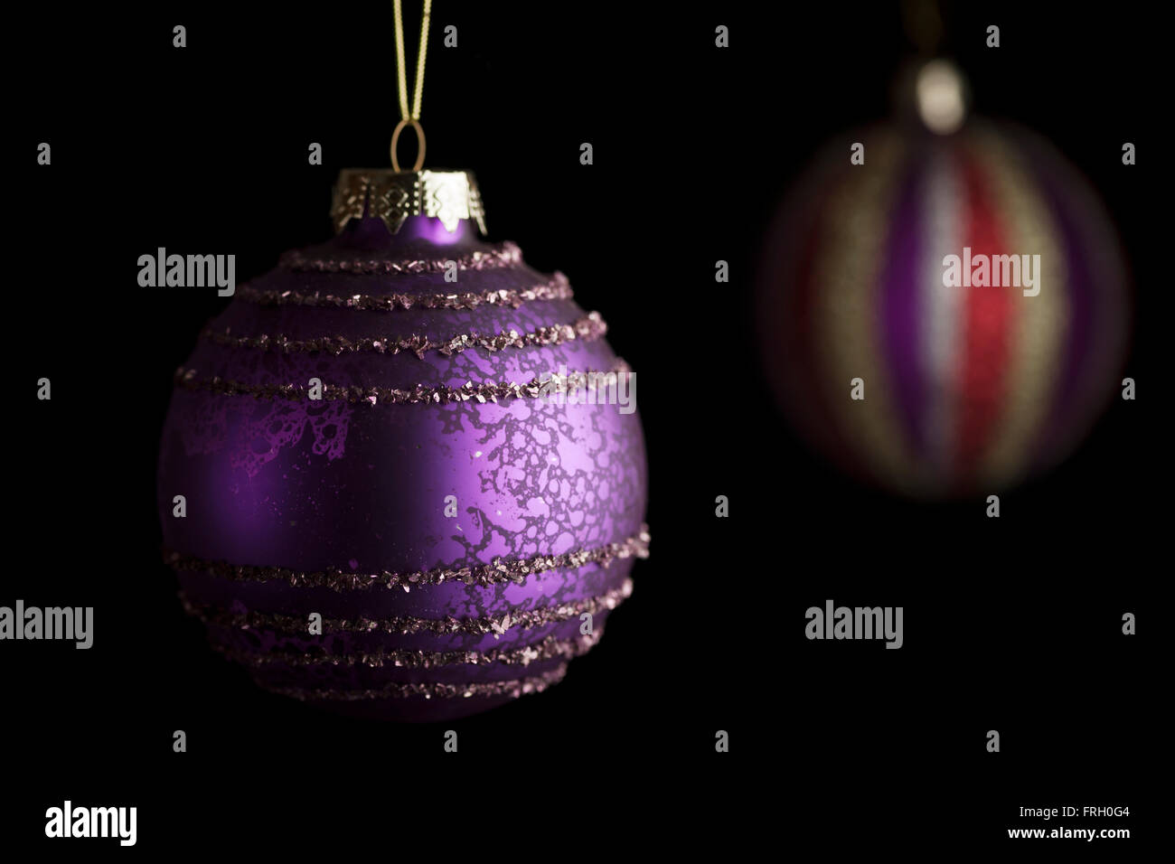 Purple Christmas ball in the foreground with vertically striped ...