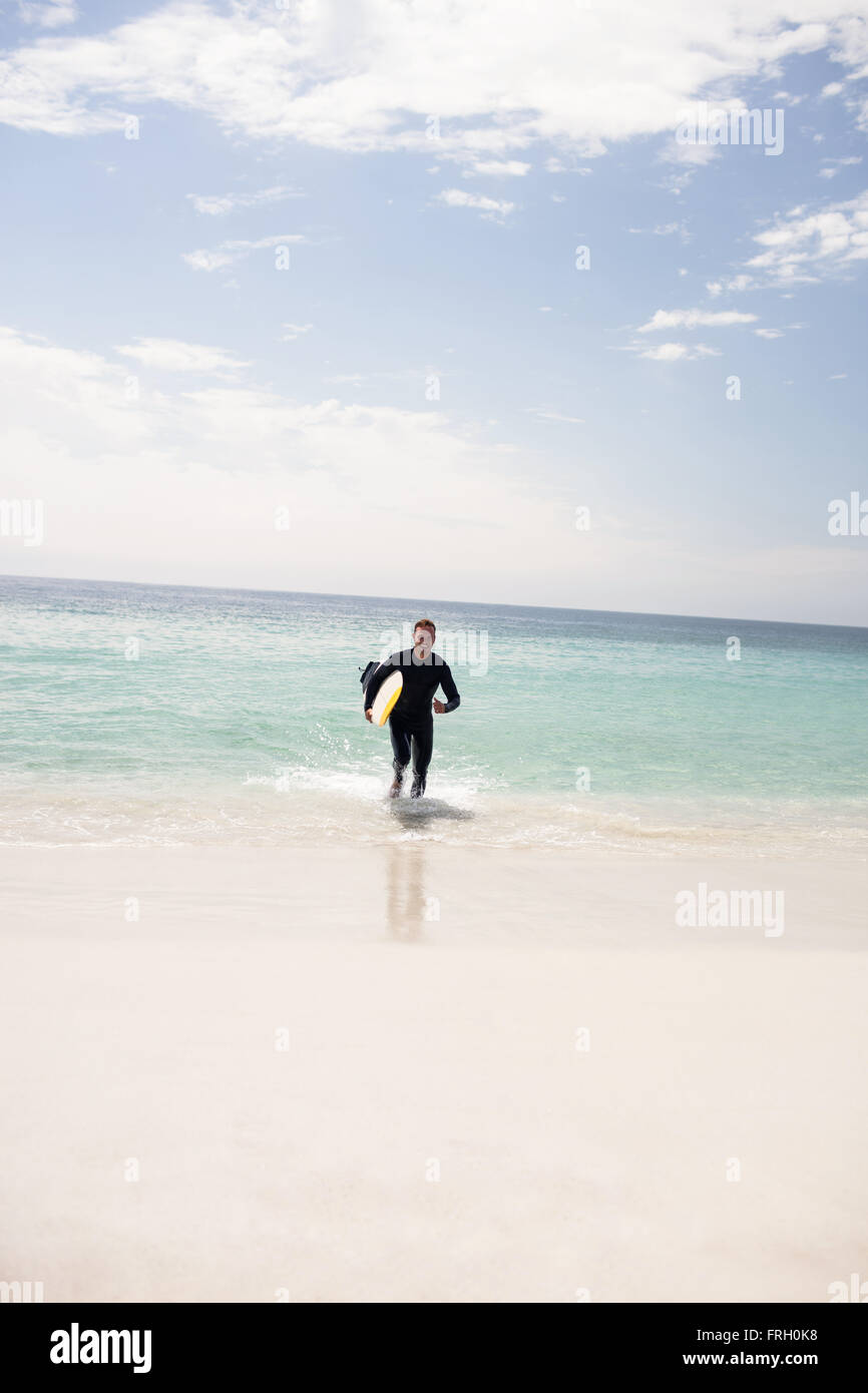 Surfer running on the beach with a surfboard Stock Photo - Alamy
