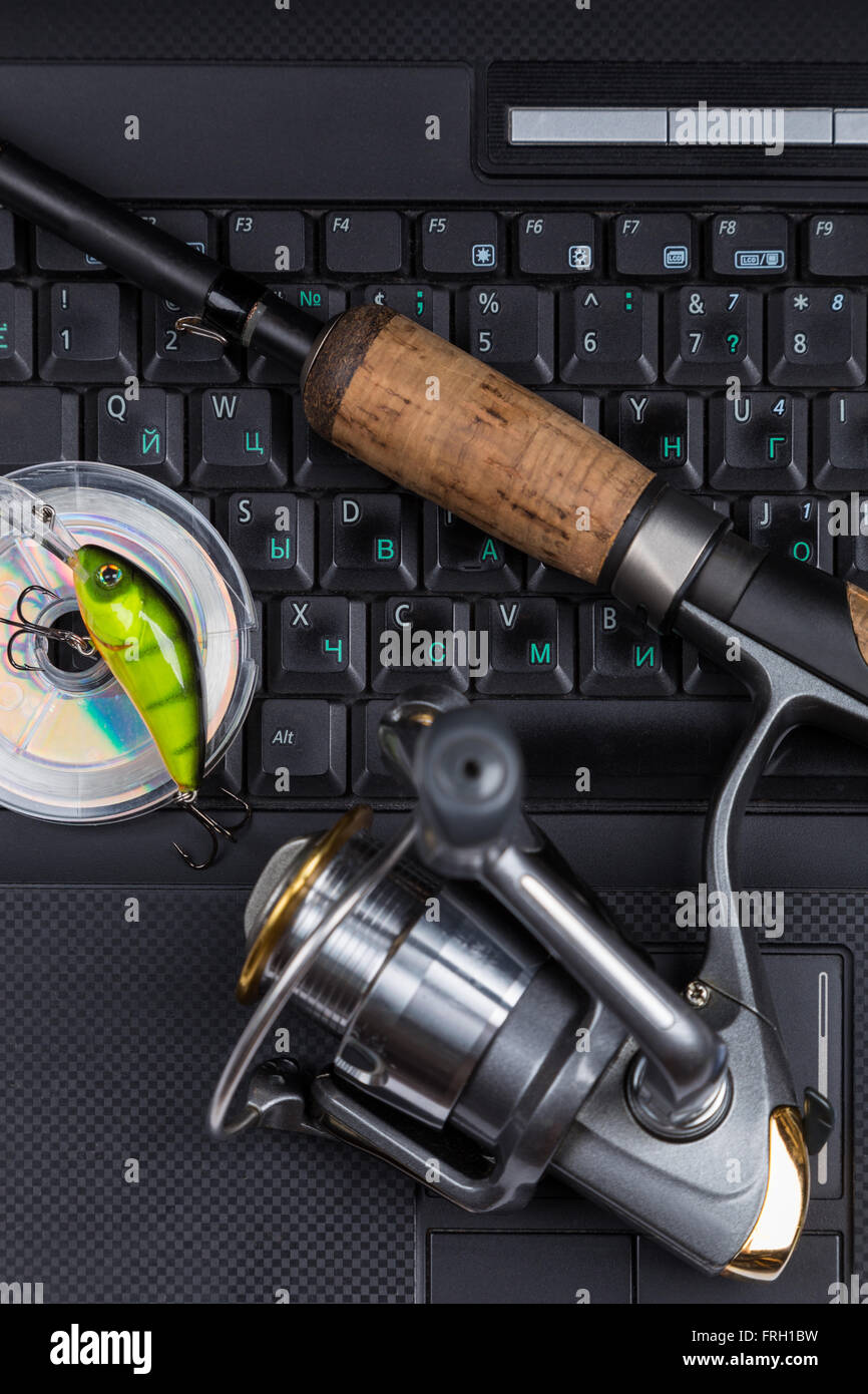 different fishing tackles on dark keyboard a black notebook. Concept ...