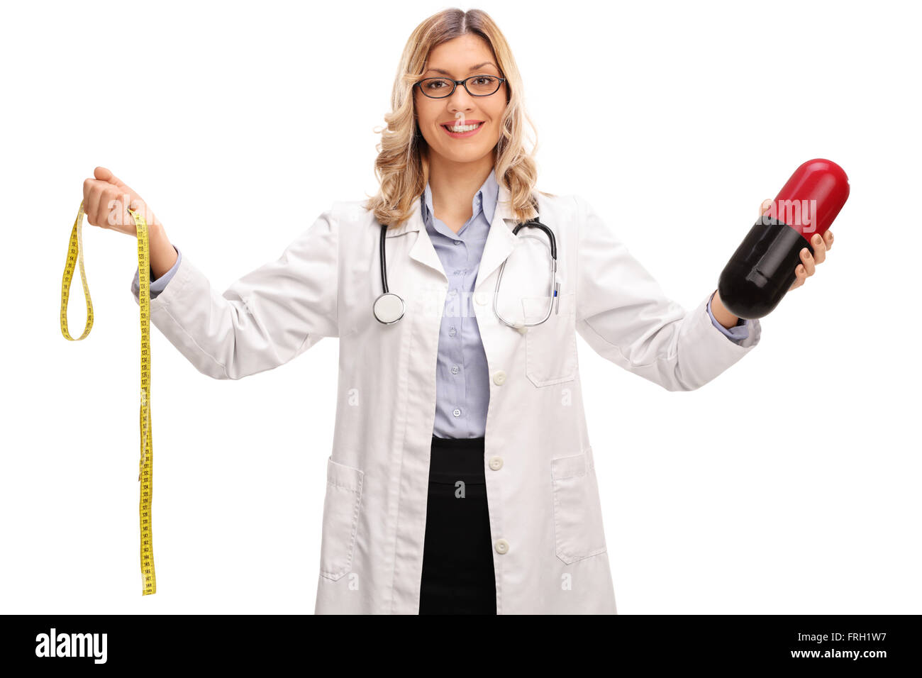 Young female doctor holding a measuring tape and a huge diet pill ...