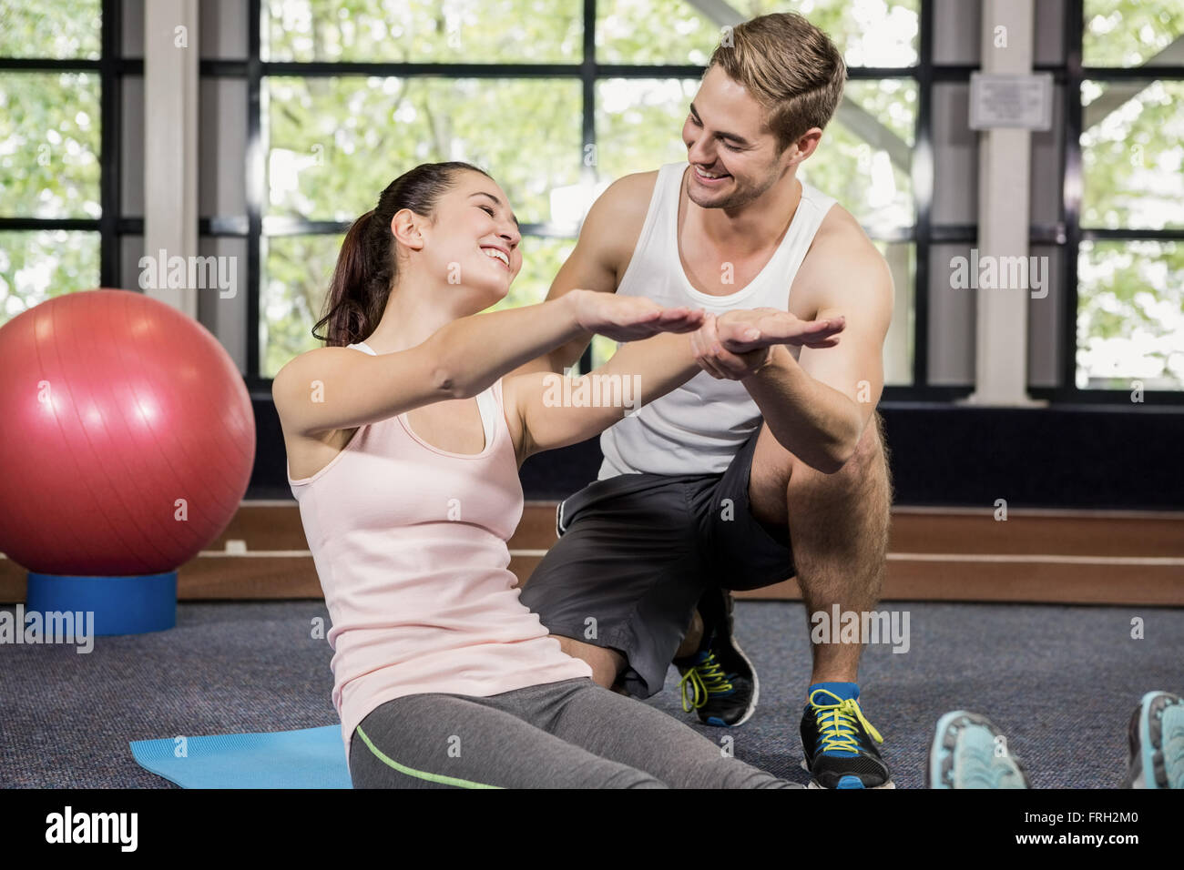 Trainer motivating a woman while doing crunches Stock Photo - Alamy