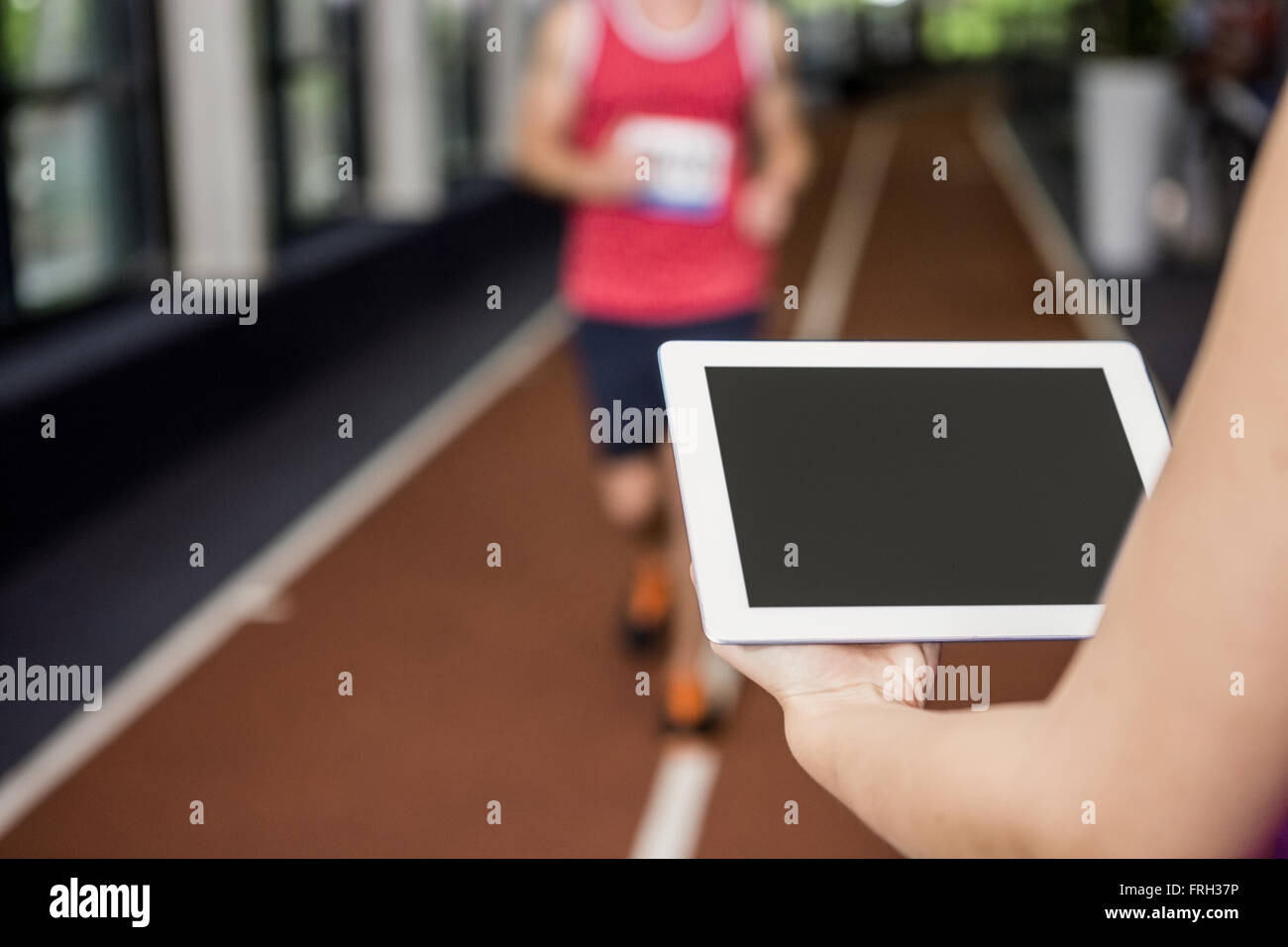 Trainer using a digital tablet while man performing running exercise ...