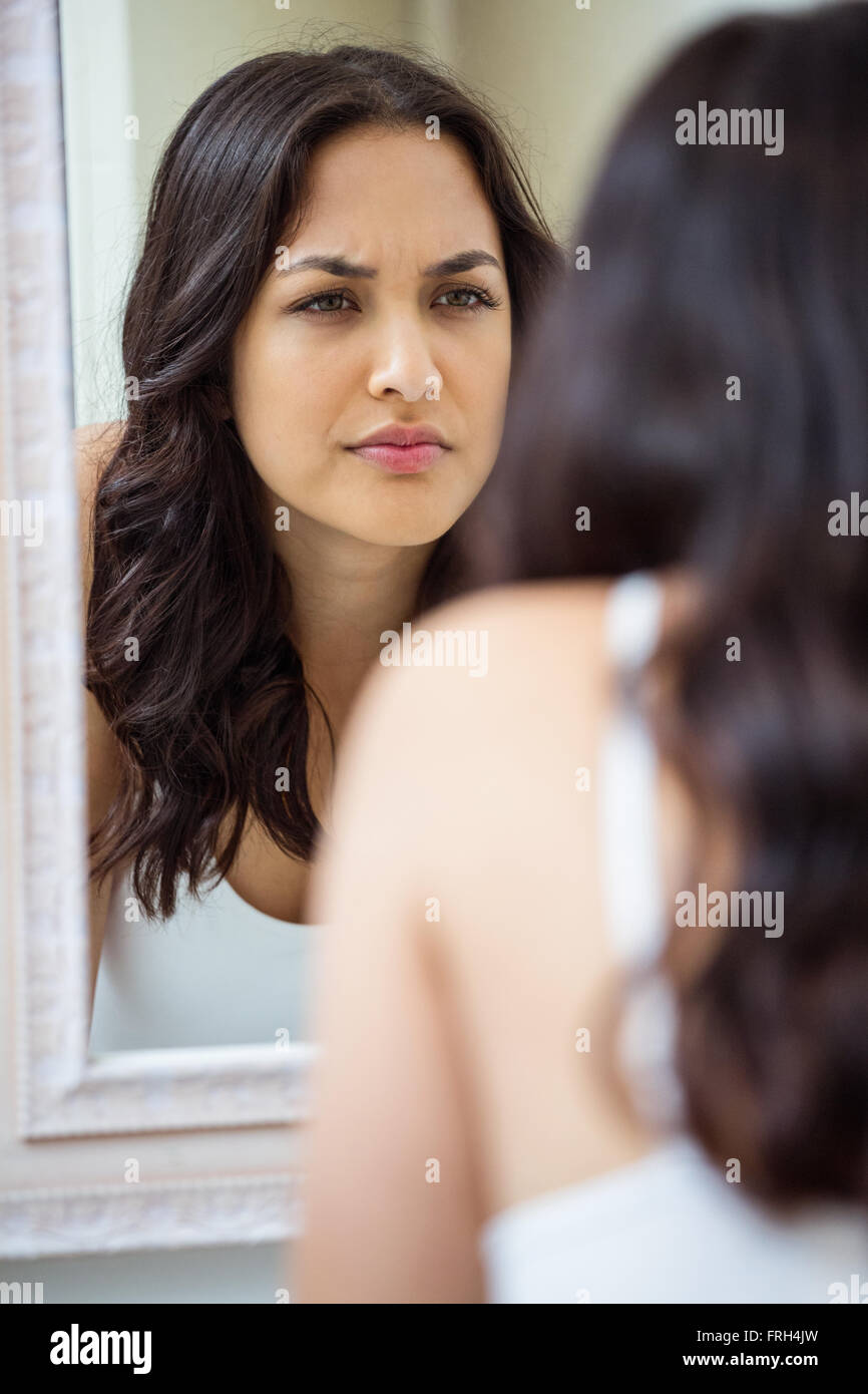Young woman looking in mirror of bathroom Stock Photo - Alamy
