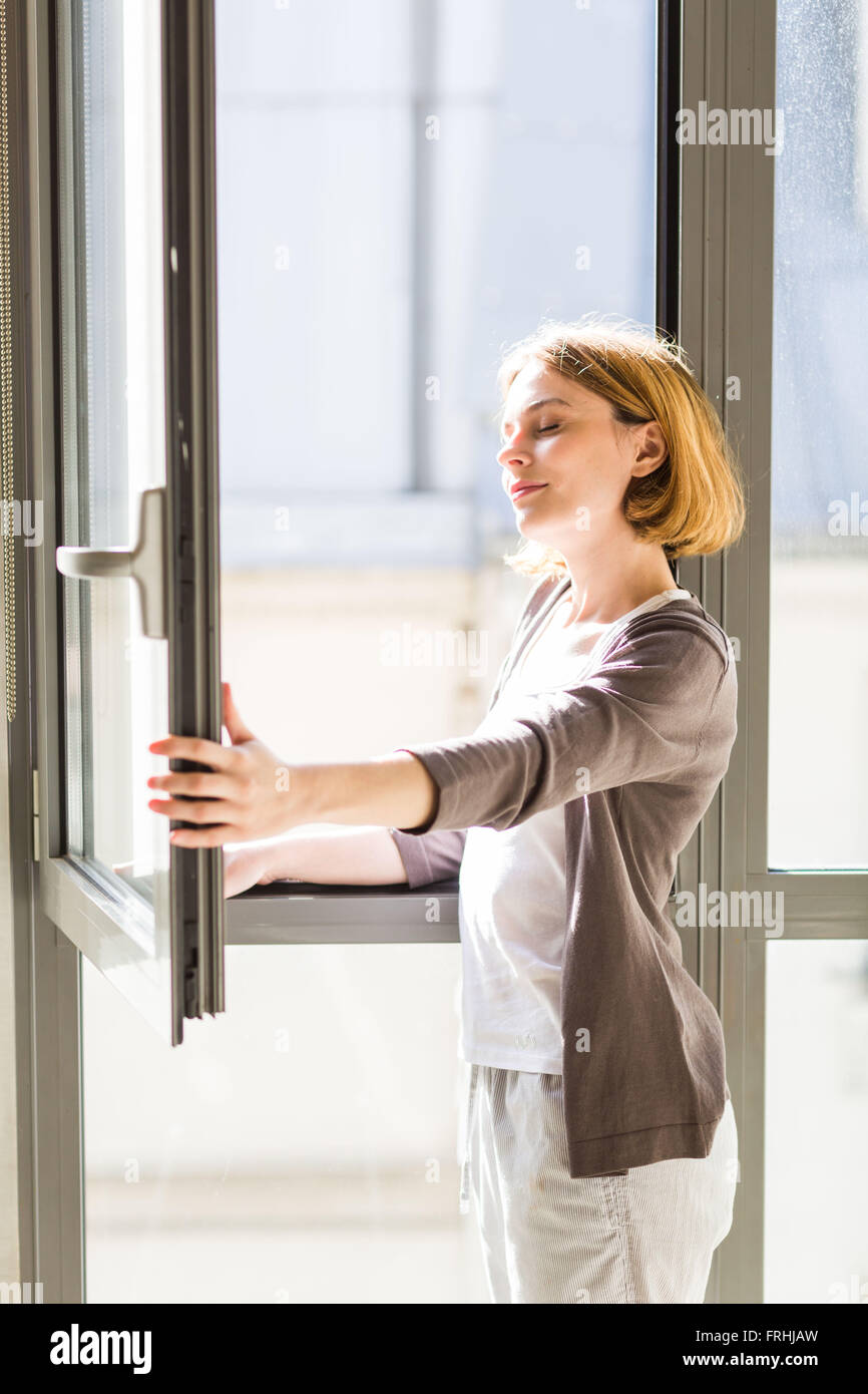 Woman opening window Stock Photo - Alamy