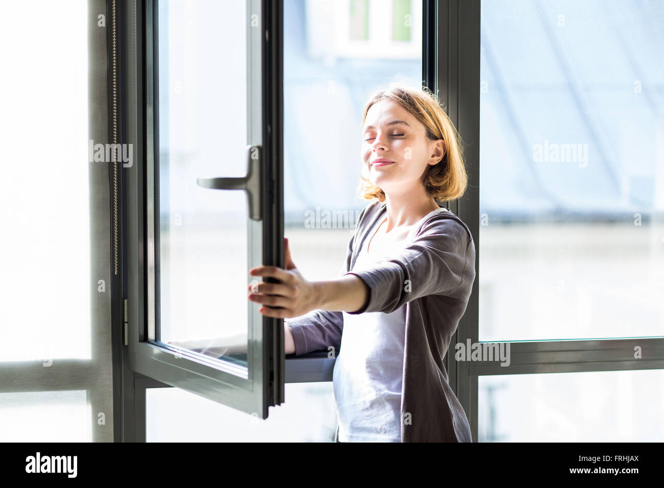 Woman opening window Stock Photo - Alamy
