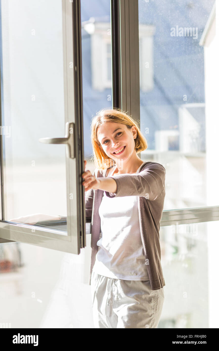 Woman opening window Stock Photo - Alamy