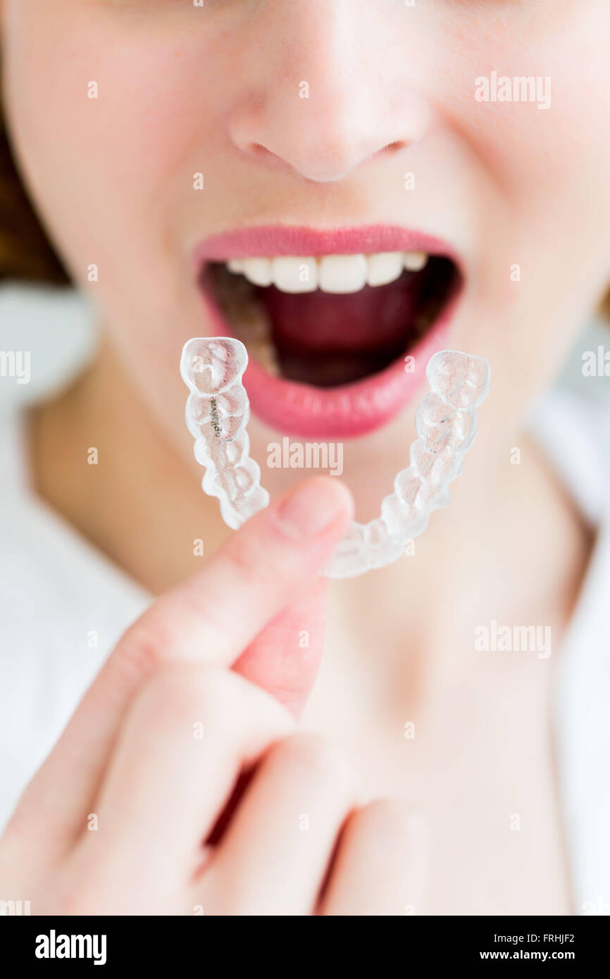 Woman using clear removable INVISALIGN aligners to straighten the teeth ...