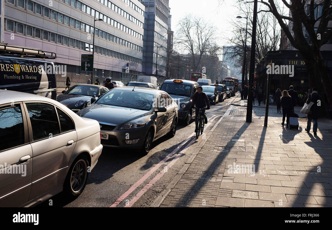 Cyclist battles with traffic in rush hour along the Euston Road London ...