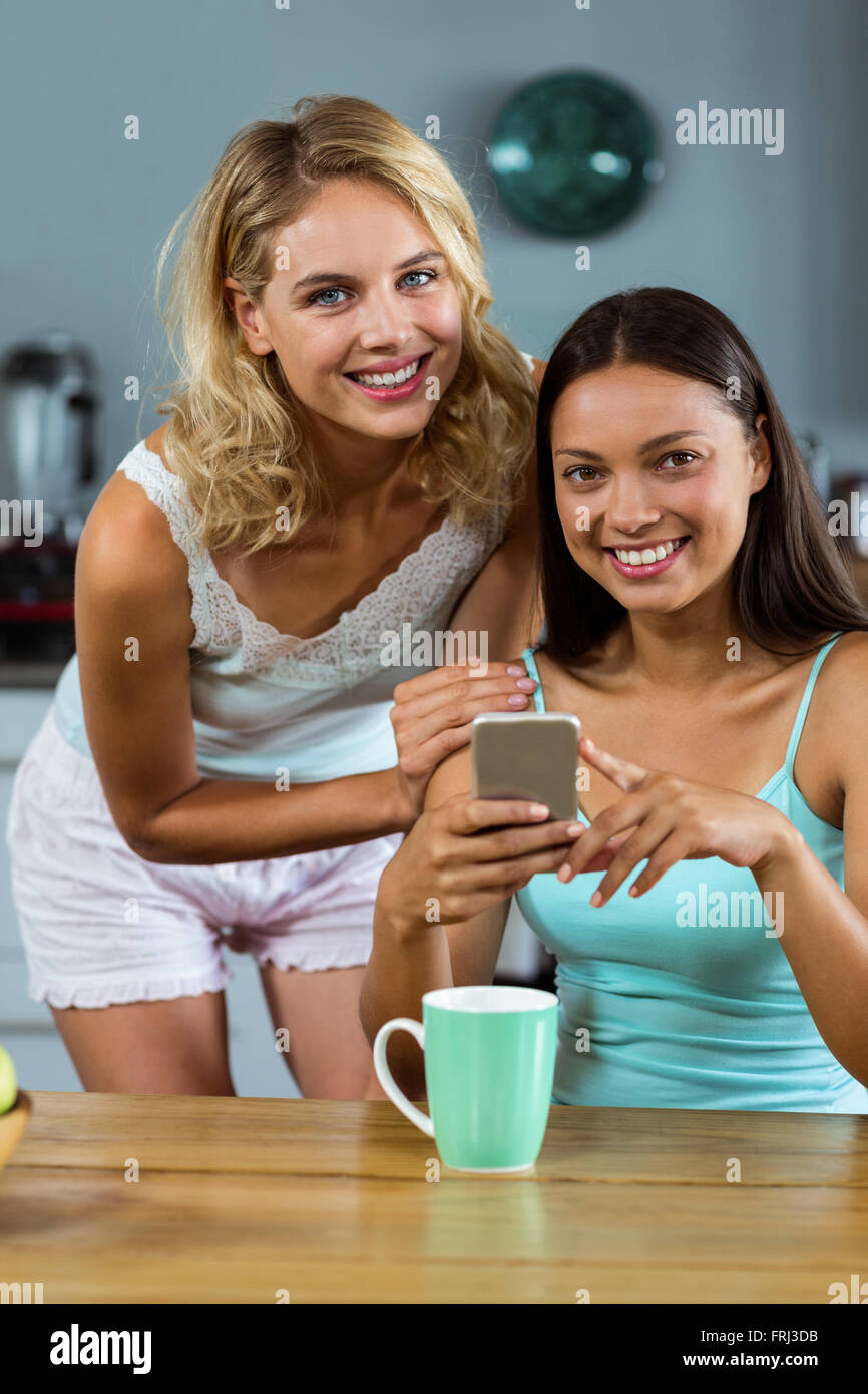 Beautiful young women using mobile phone at home Stock Photo - Alamy