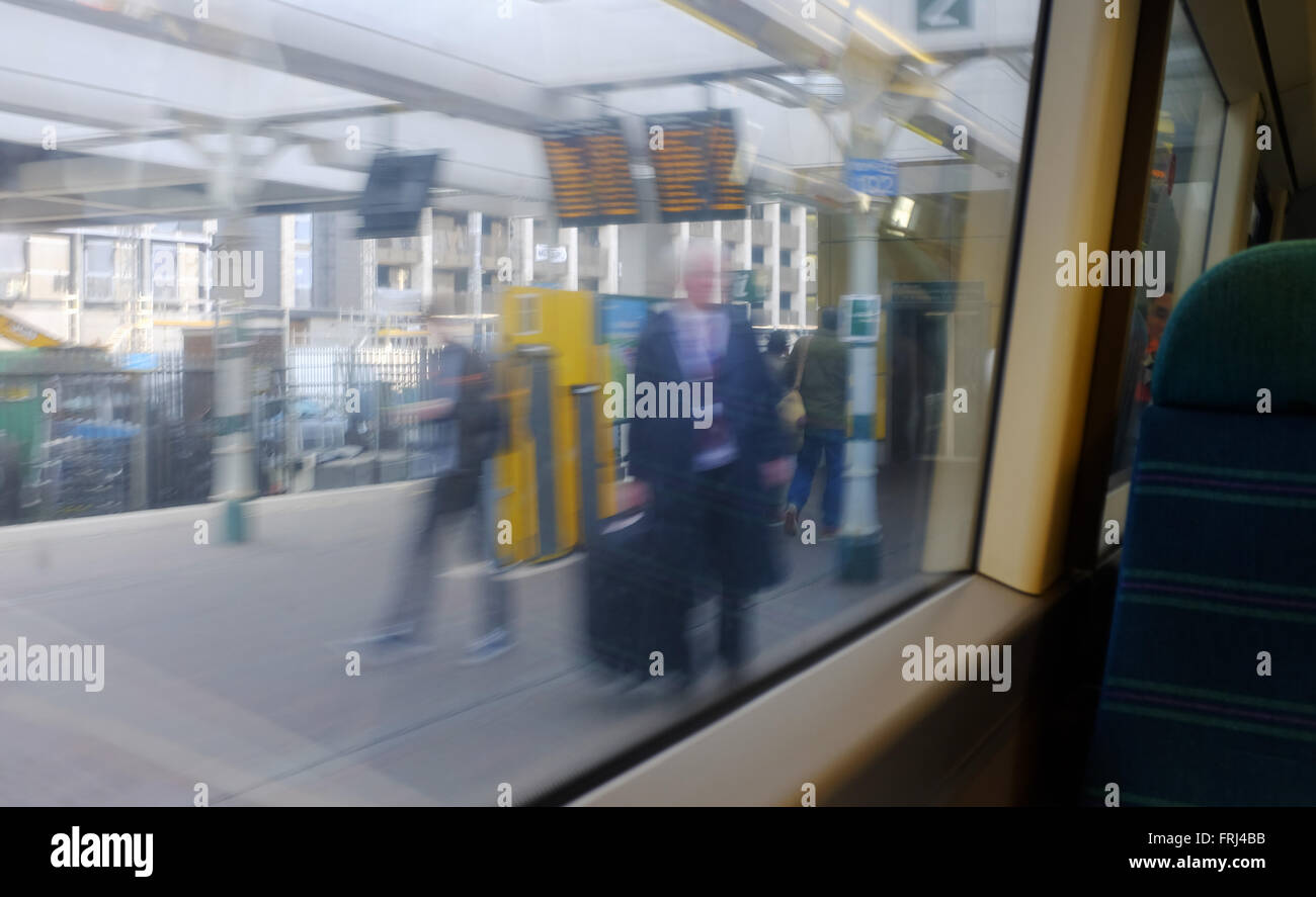 View looking out of train window at commuters on railway station ...