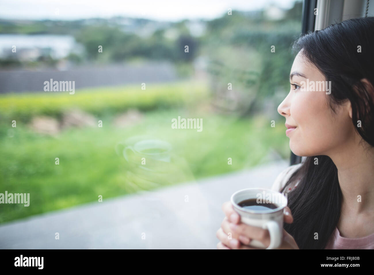 Happy woman looking through window Stock Photo - Alamy